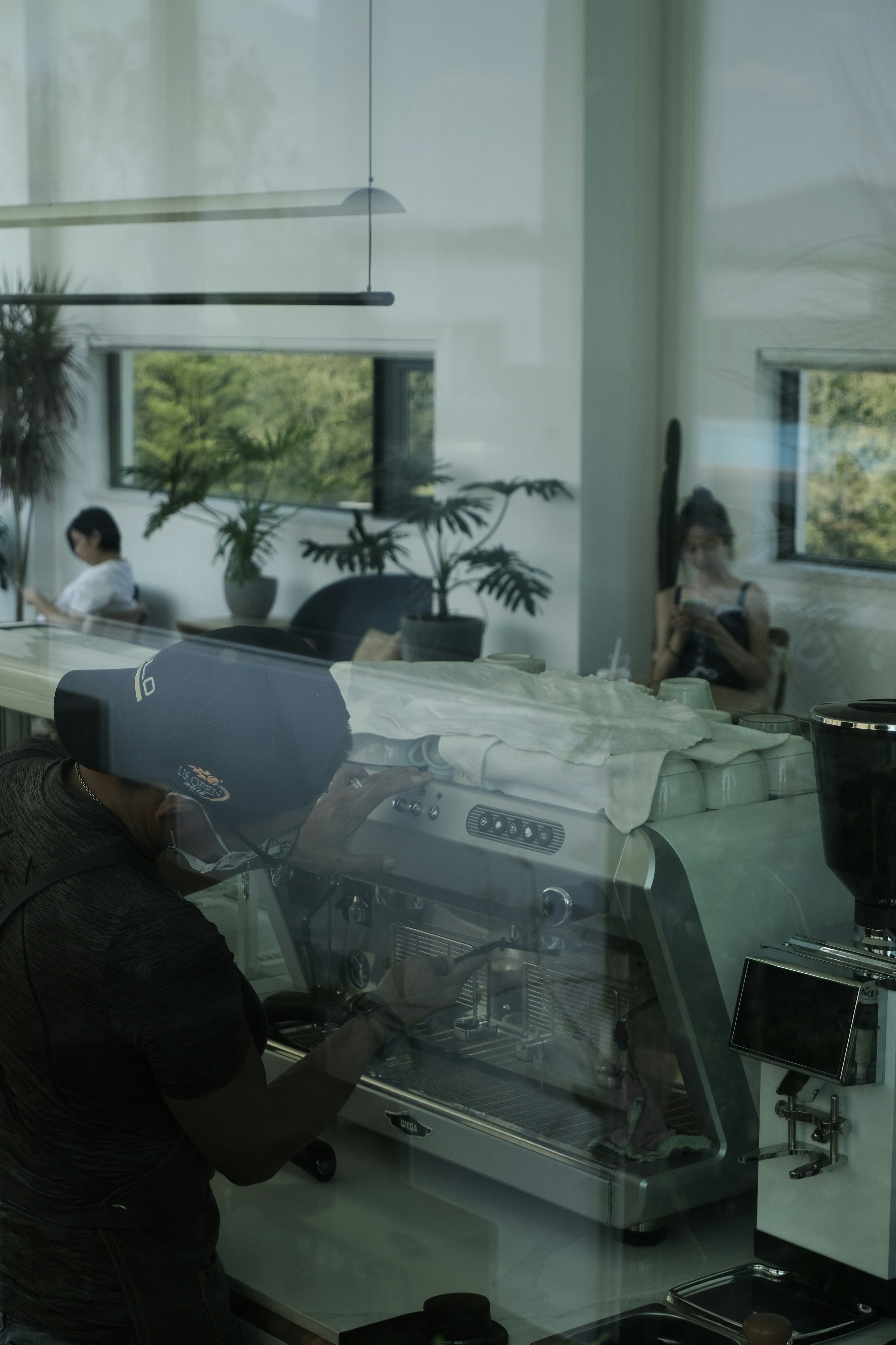 Through Glass: Barista at Work Beyond a Quiet Kitchen Garden