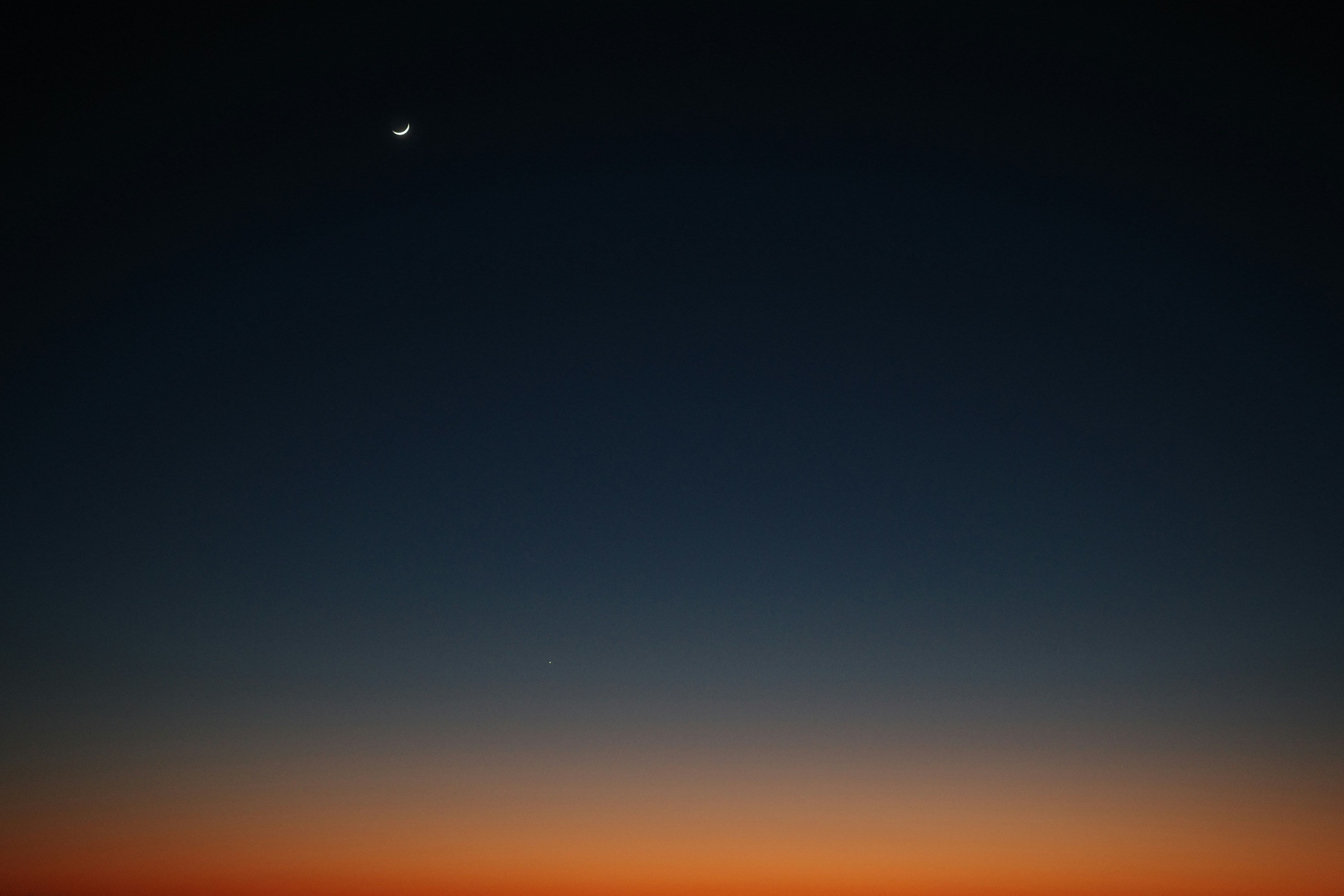 Crescent Moon Above a Quiet Horizon at Sunset