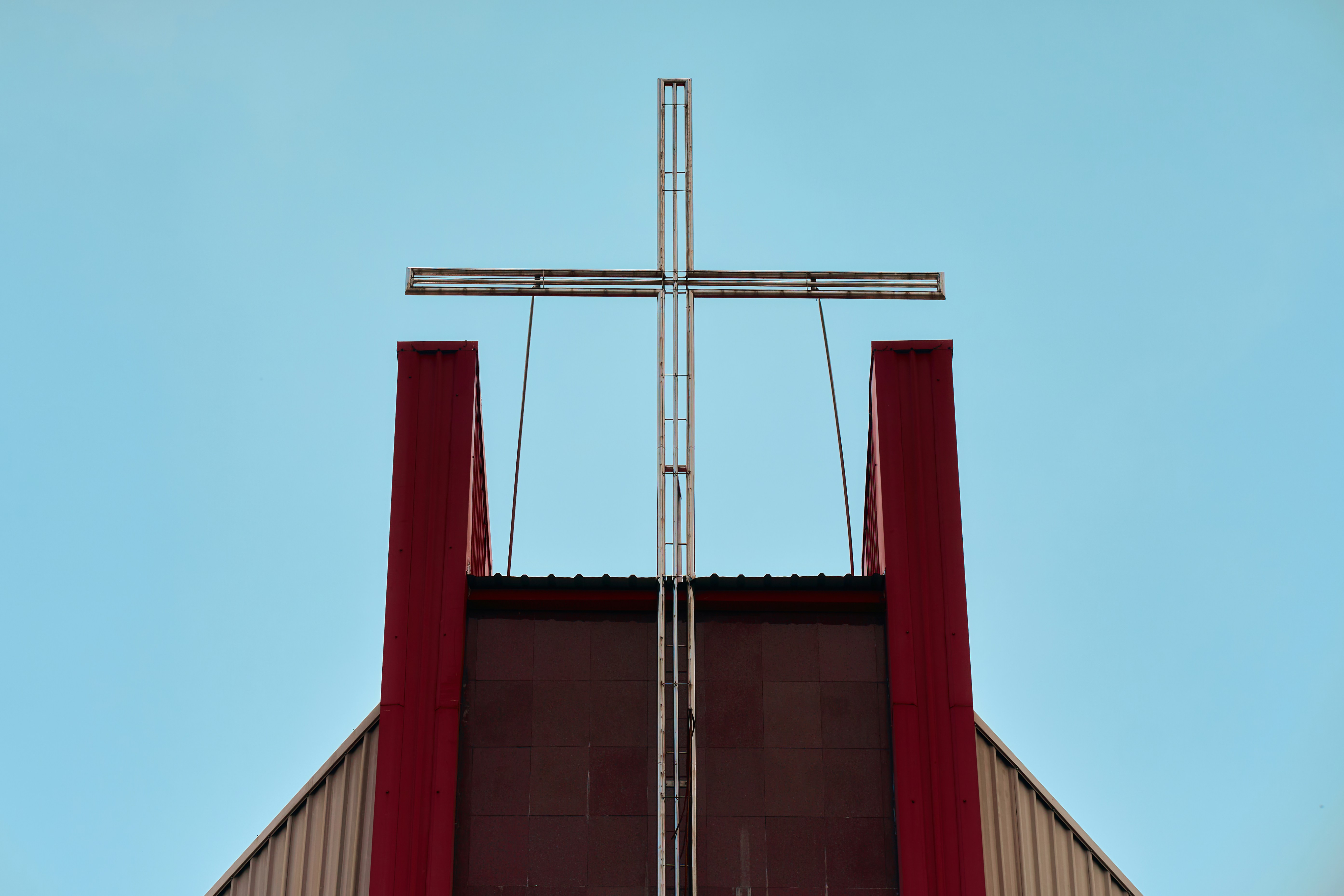 Cross atop achurch tower under a pale blue sky