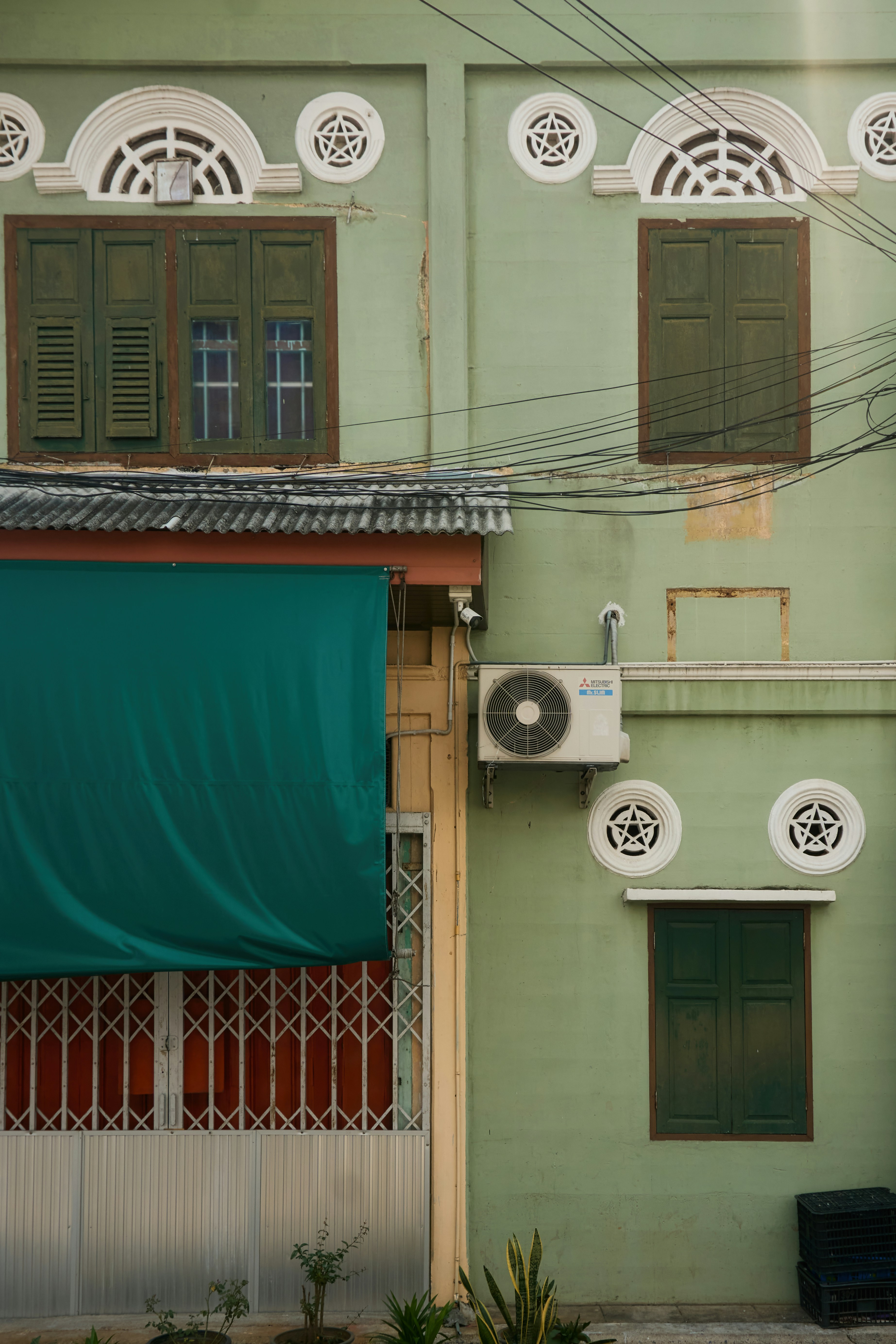 Green Facade with Teal Awnings and Architectural Circles