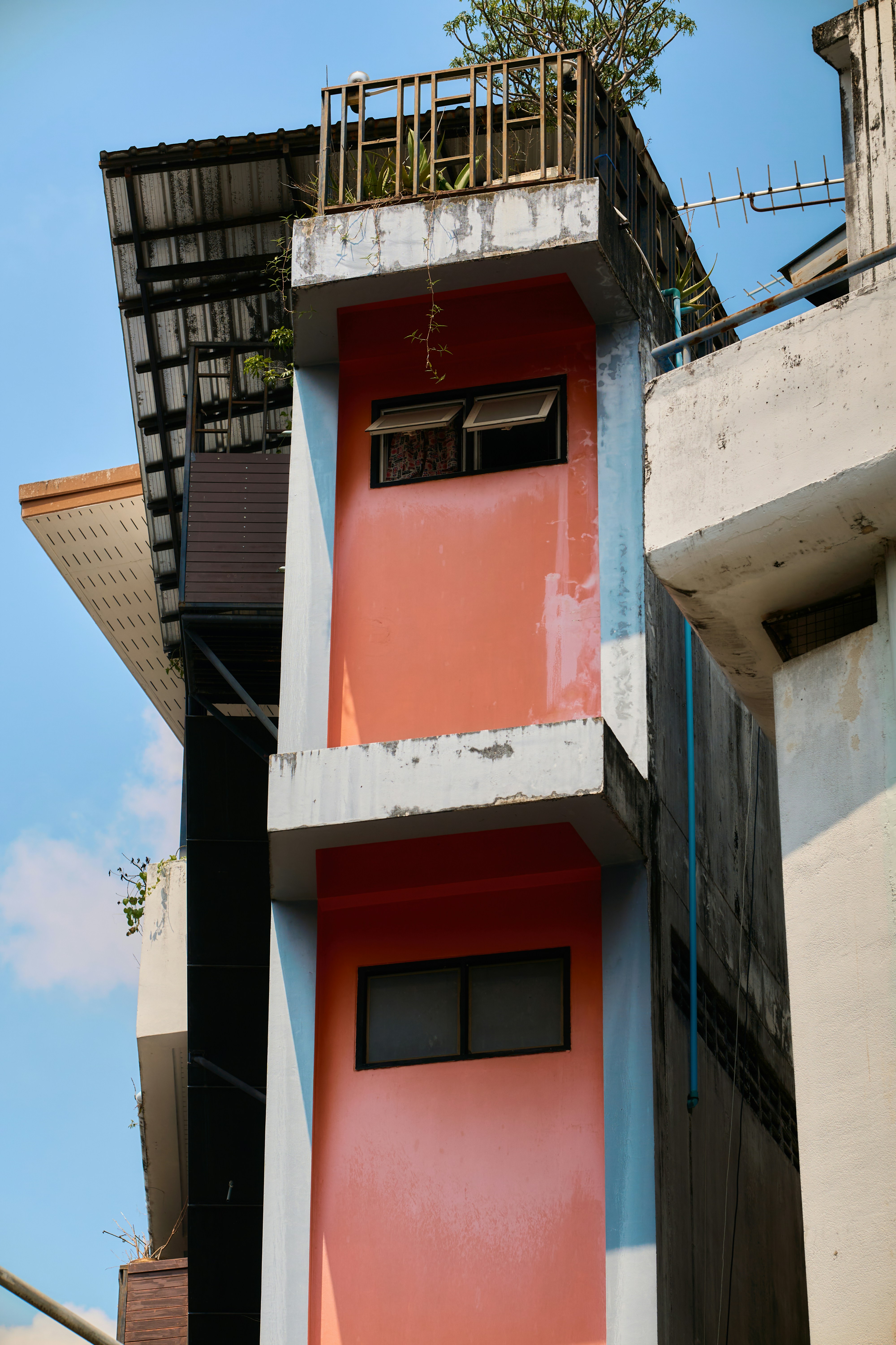 Red-Orange Facade Rising Above a Weathered Balcony