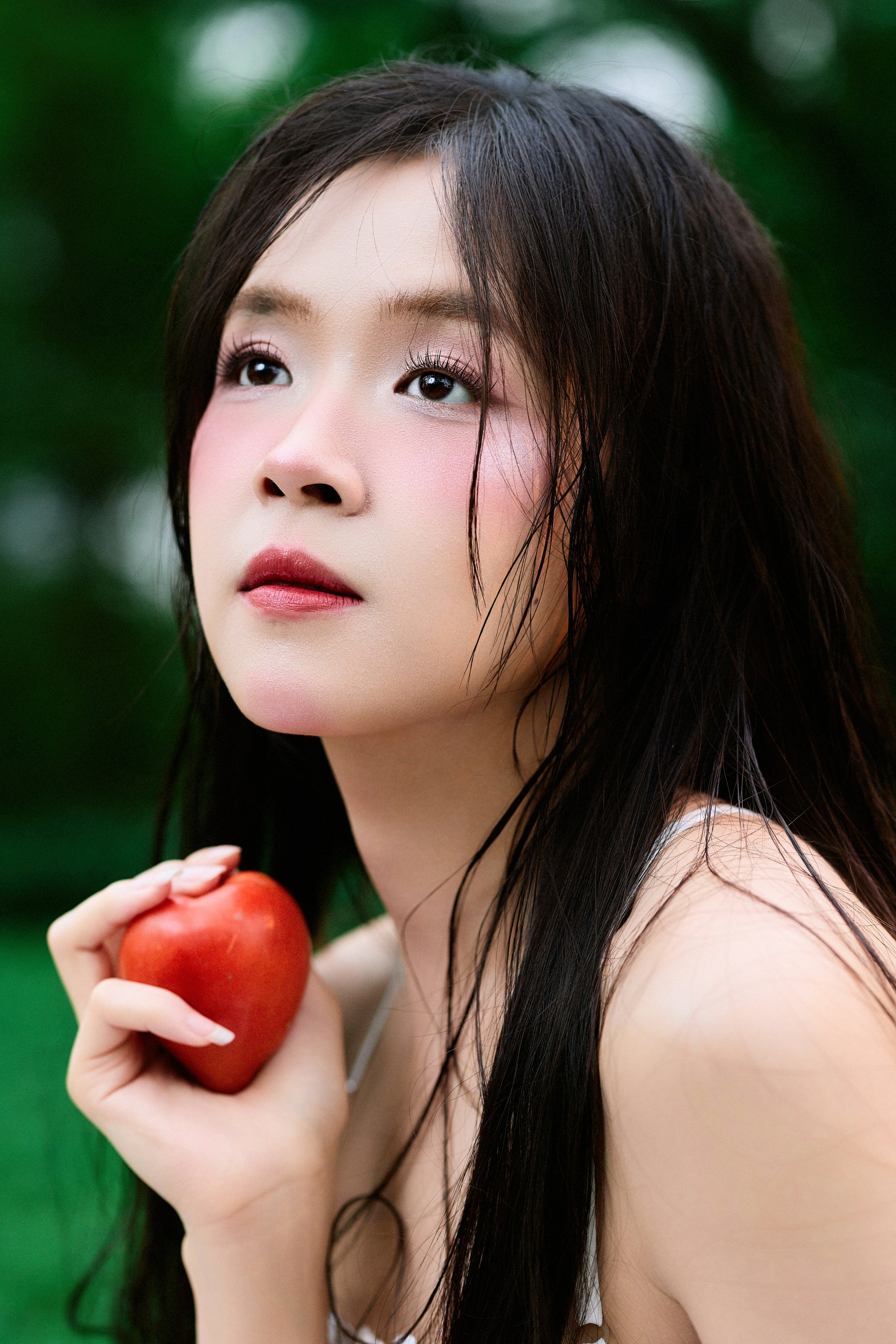 Soft-eyed portrait of a serene young woman holding a red apple