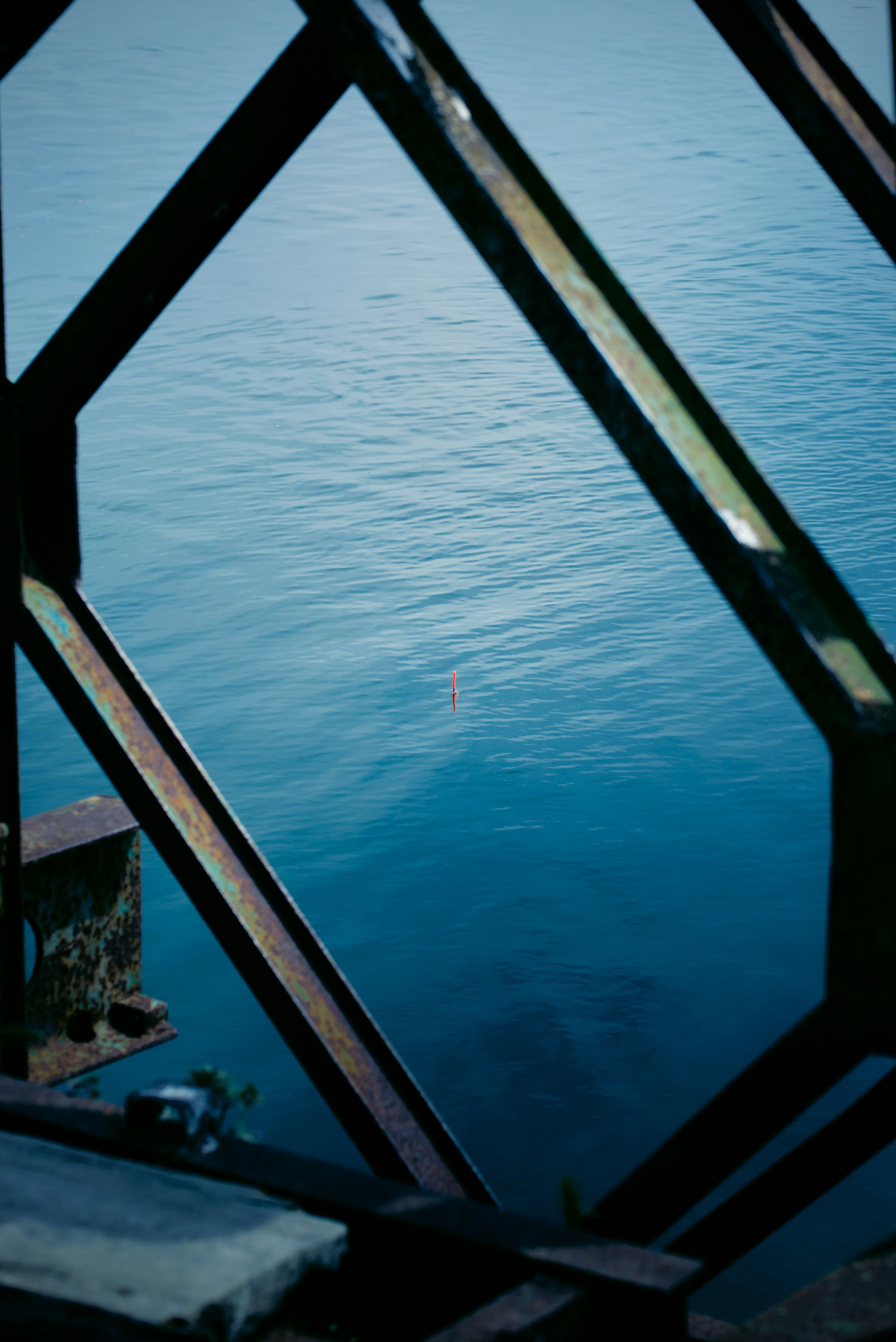 Rusted girders Framing a Quiet Blue Abyss