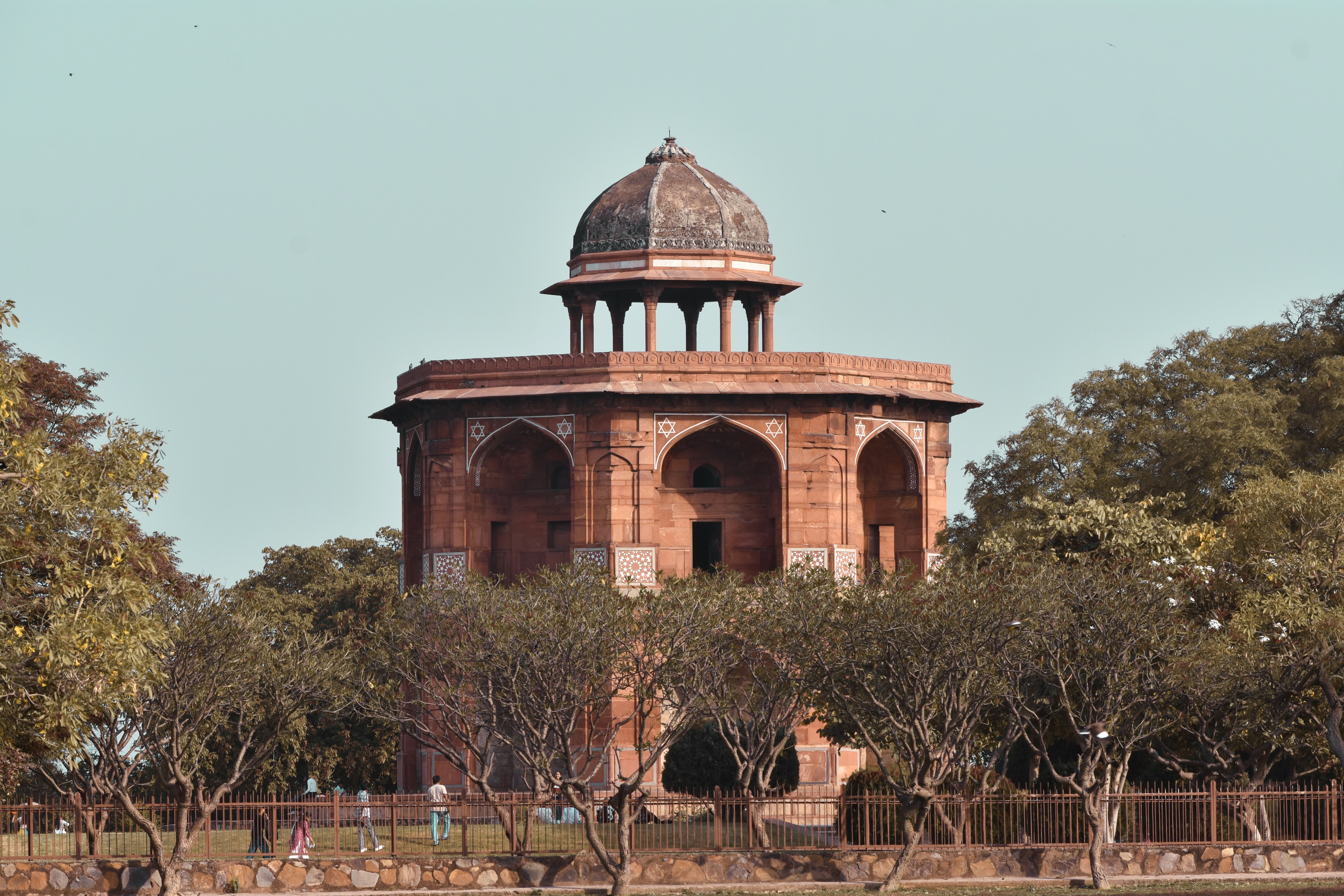 Red sandstone folly rising above a tree-lined park