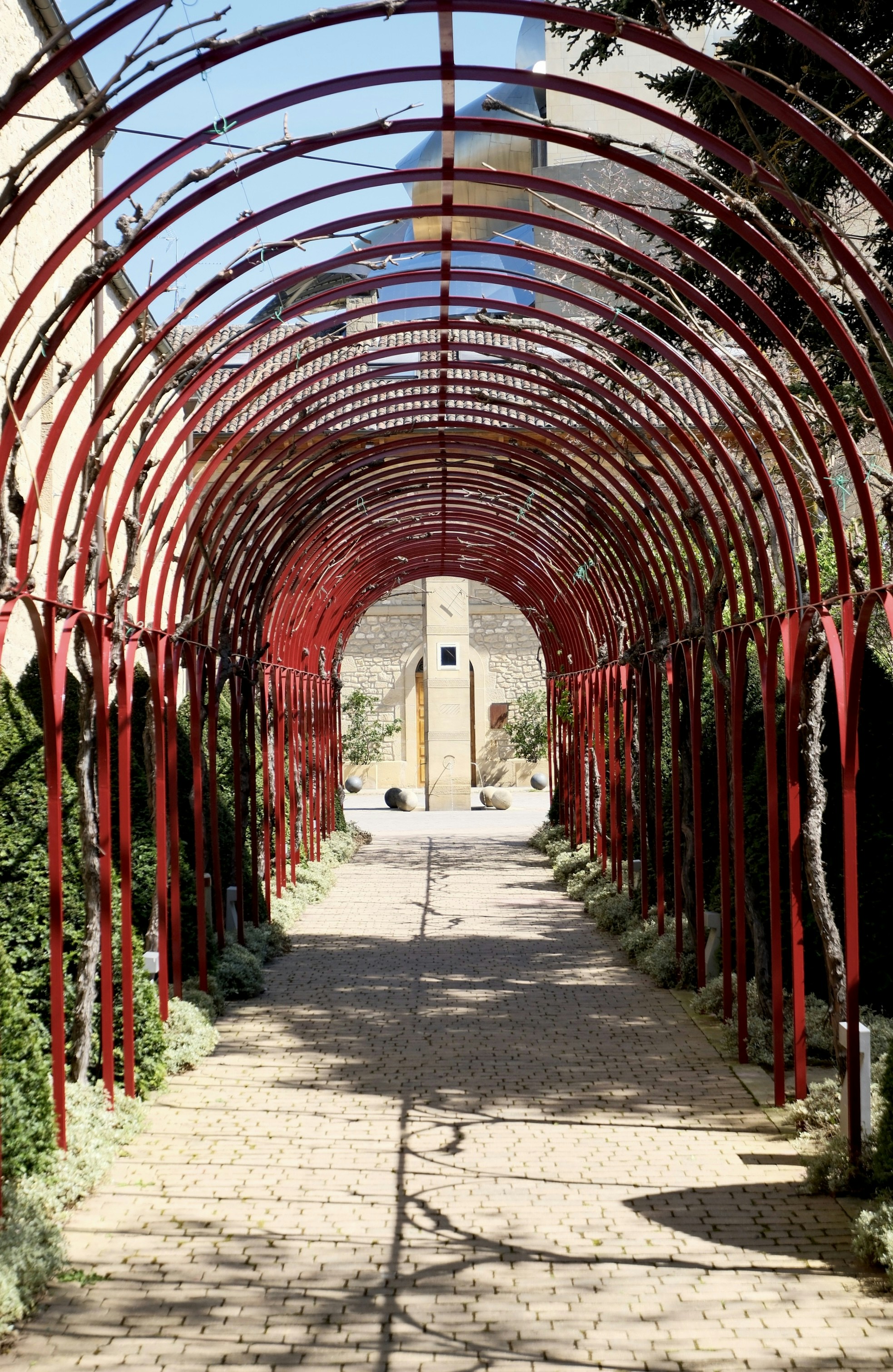Red Archway Corridor: A Sunlit Path Through Forged Curves