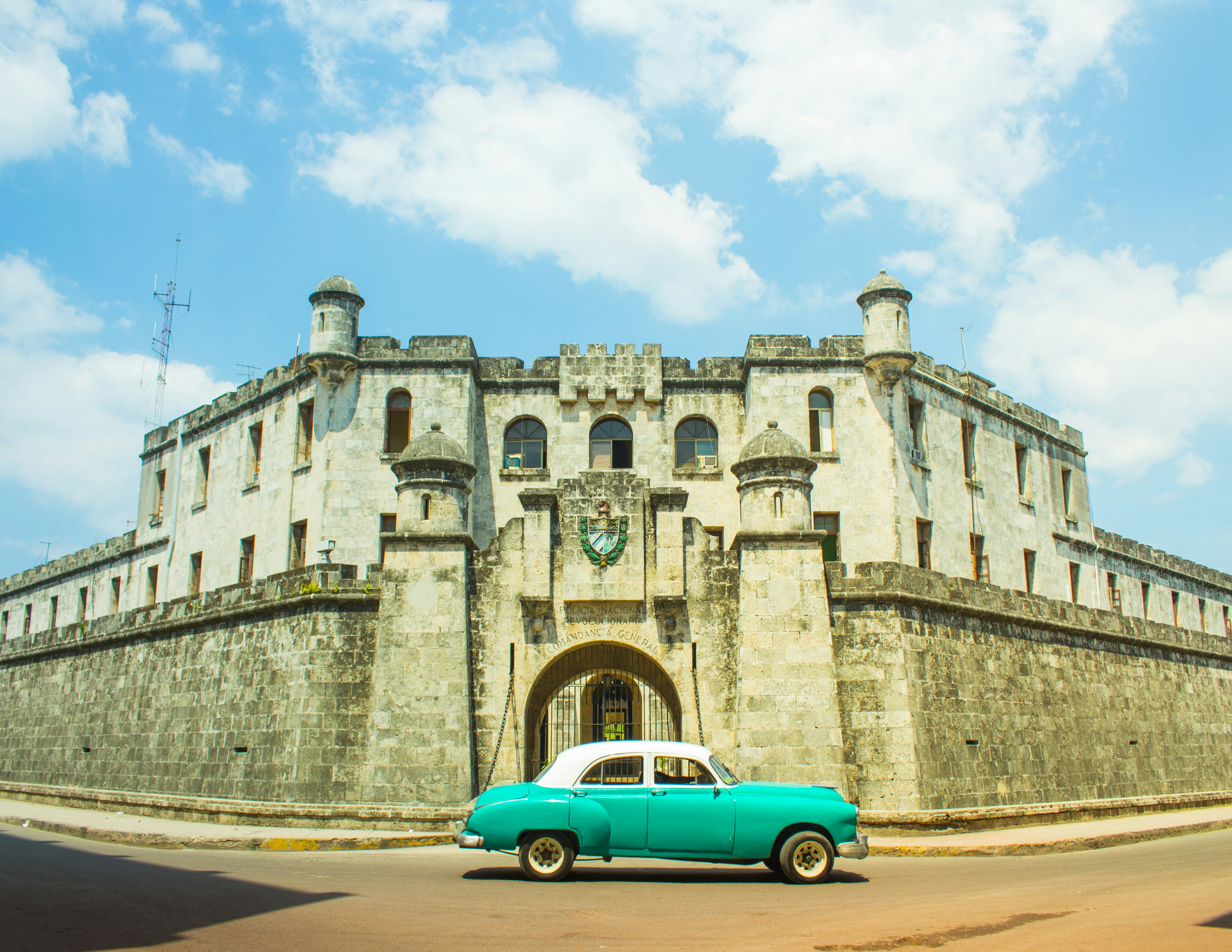 Teal Classic: A Vintage Car Before a Fortress Front