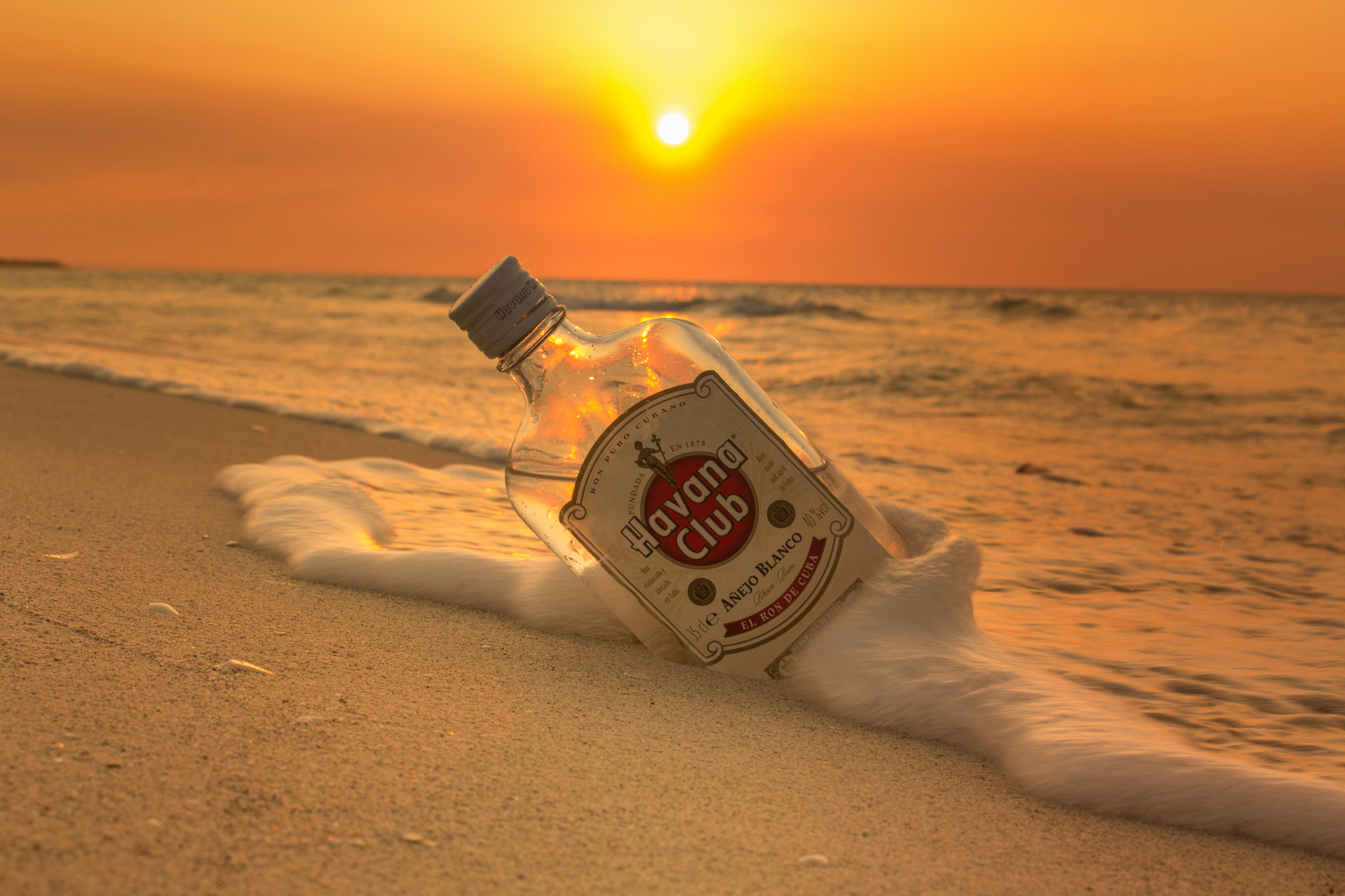 Sunset Spill: A Glass Bottle Beached by the Foamy Edge