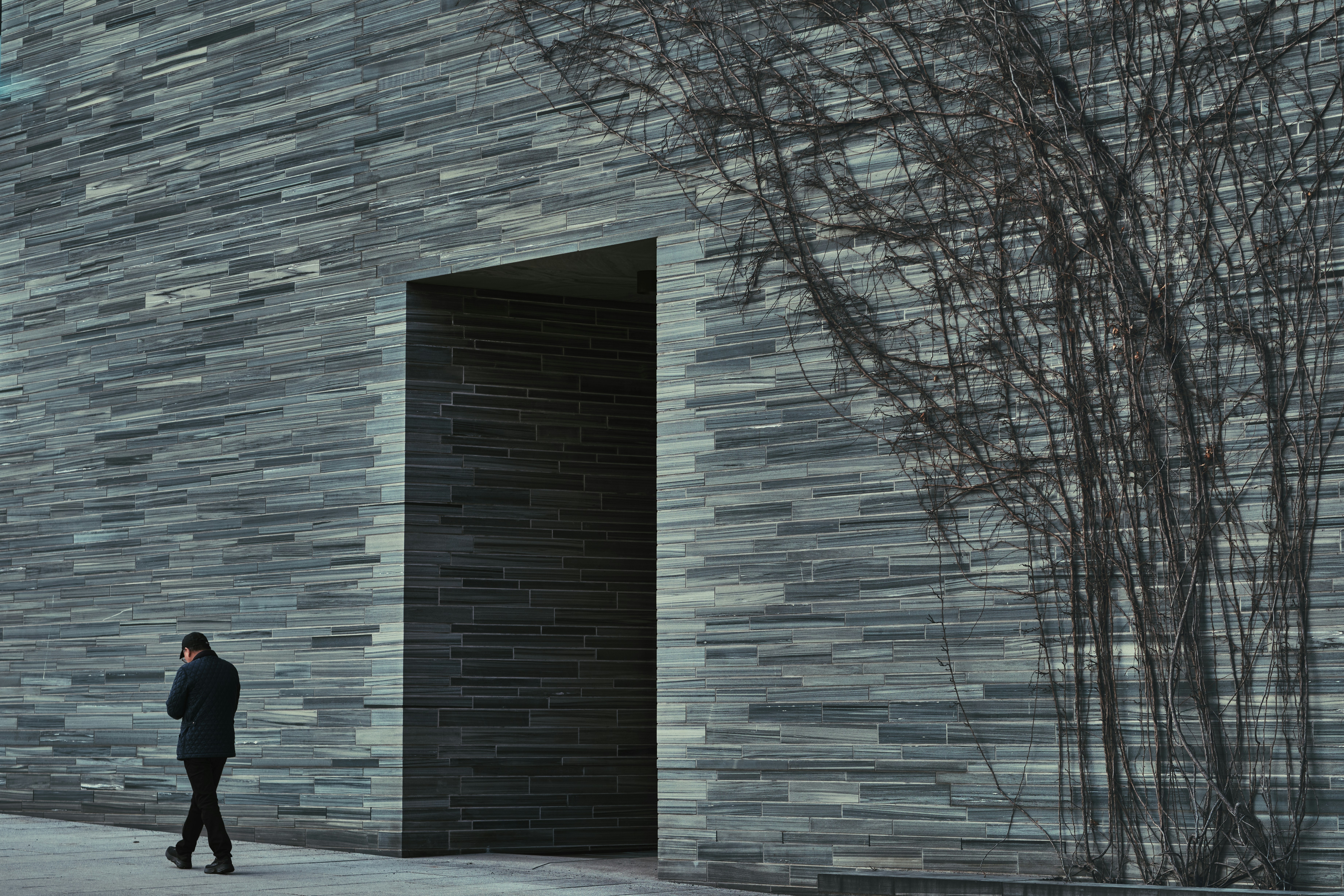 Man in silhouette steps toward a doorway carved in layered stone