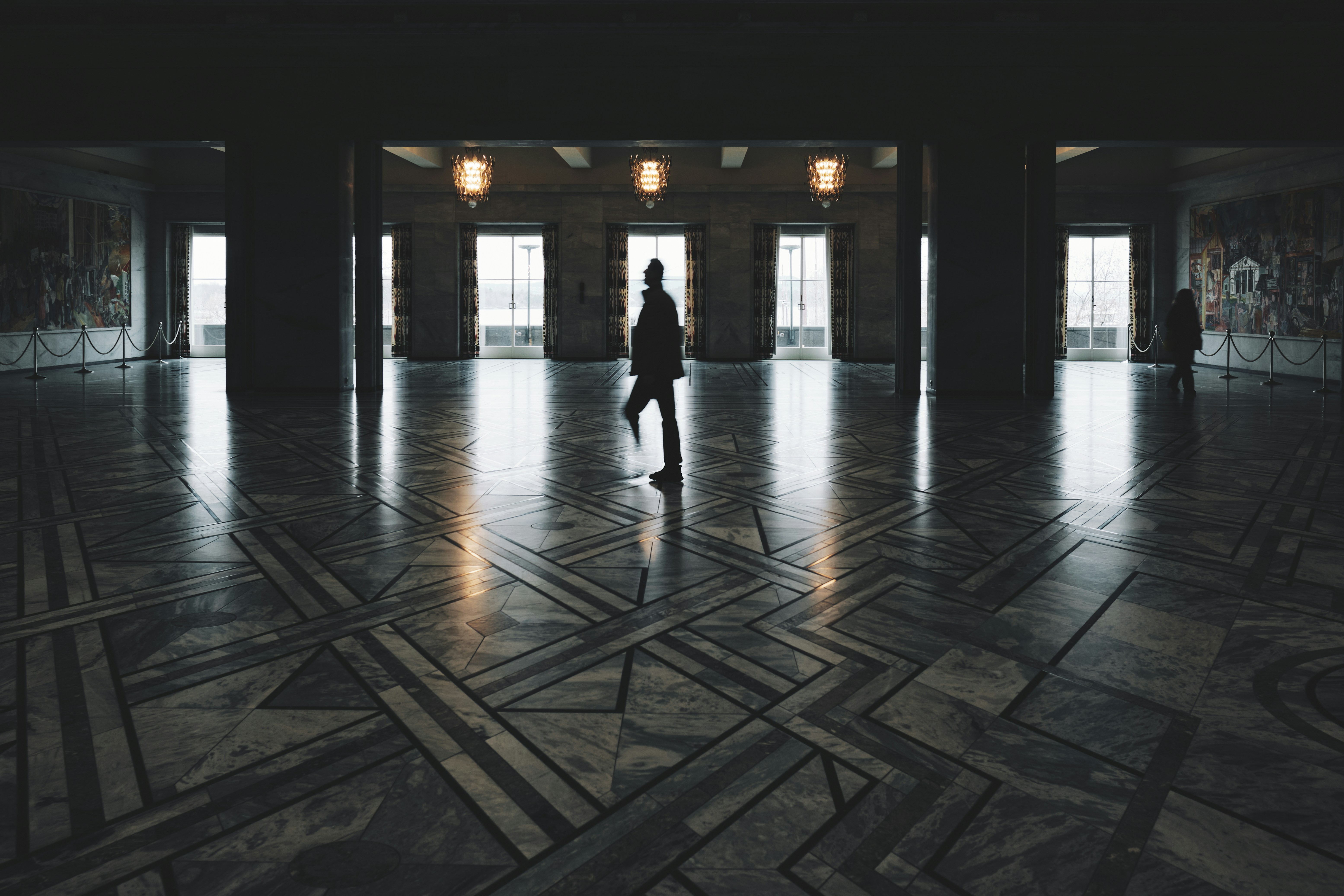 Silhouette at the Threshold: A Lone Figure in a Geometric Hall