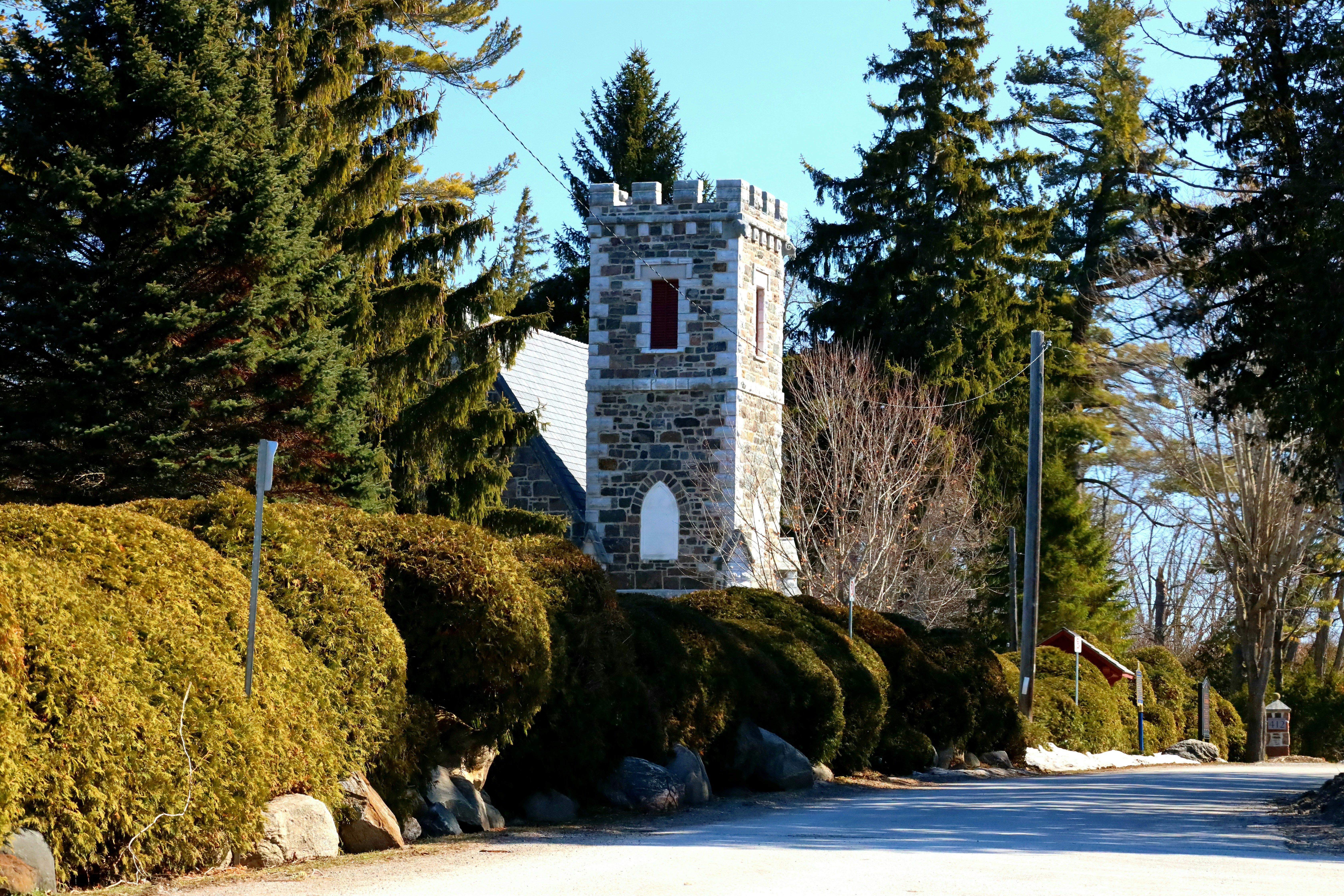 Castle-of-the-hedge: a stone tower tucked along a tree-lined road