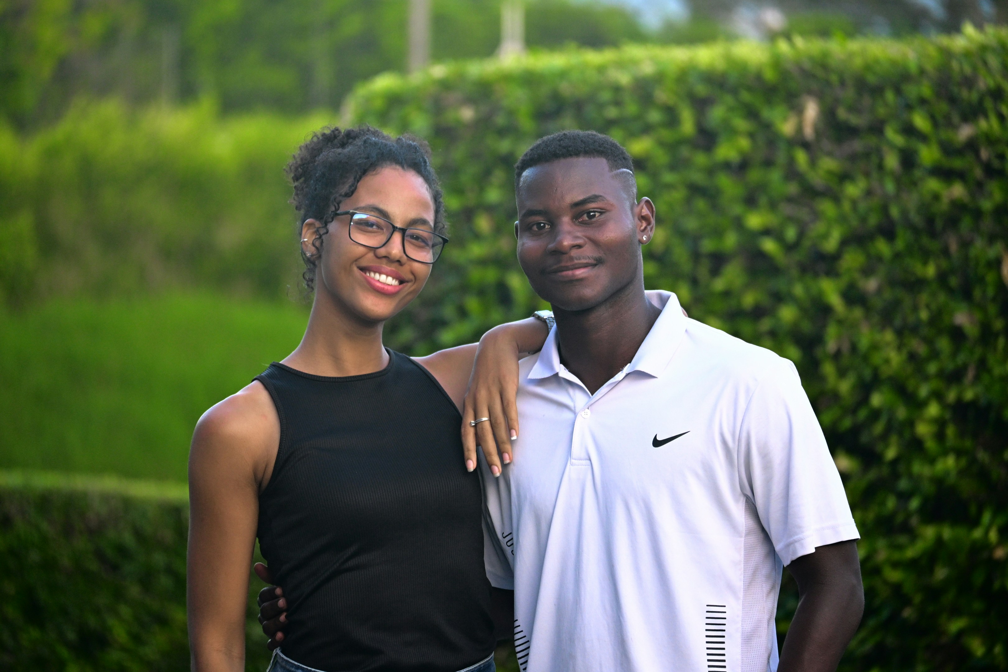 Two Friends in Sunlit Privacy: Casual Confidence Under a Green Backdrop