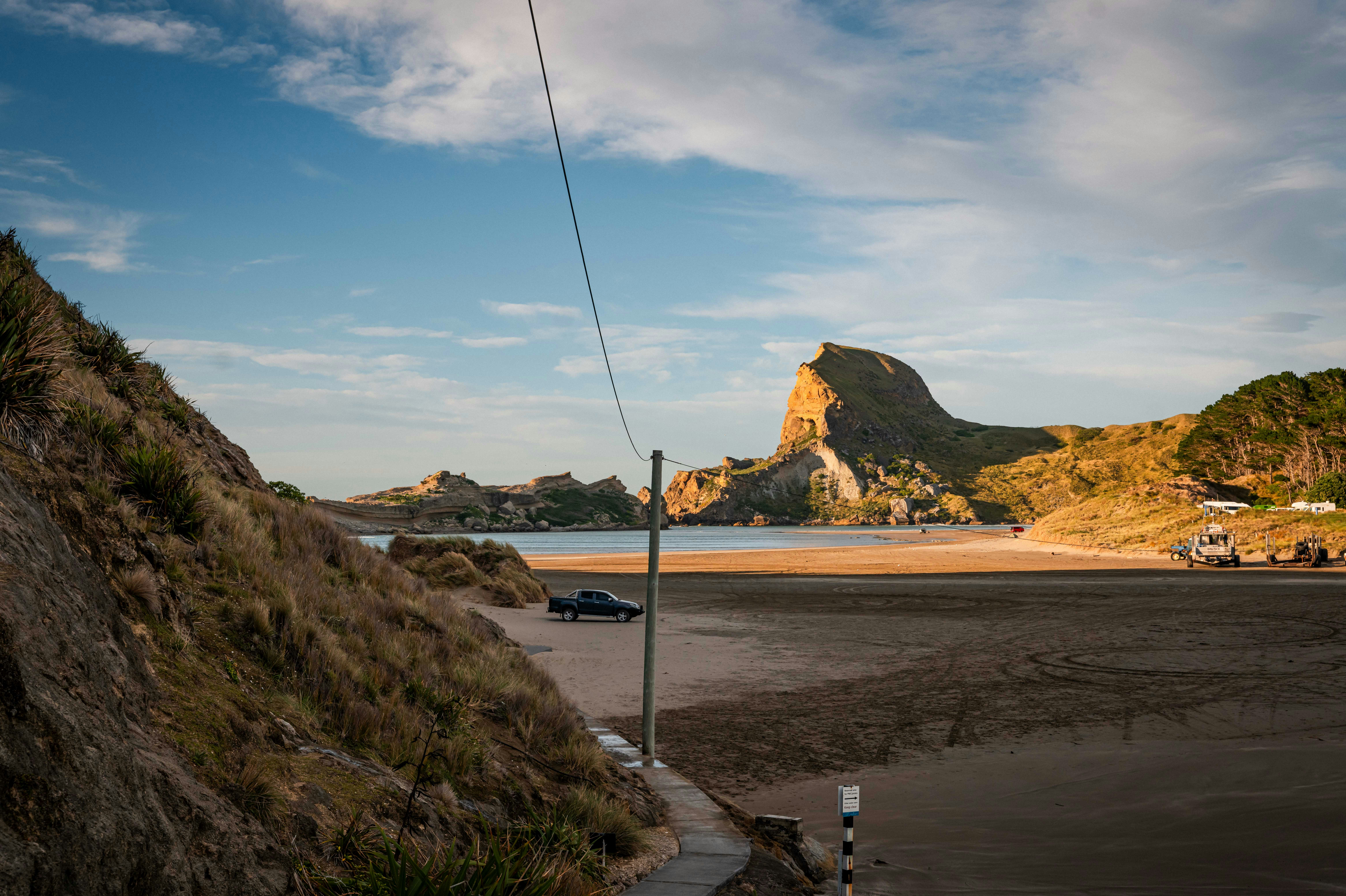 Coastal Ridge and Quiet Beach Beneath a Lone Cable
