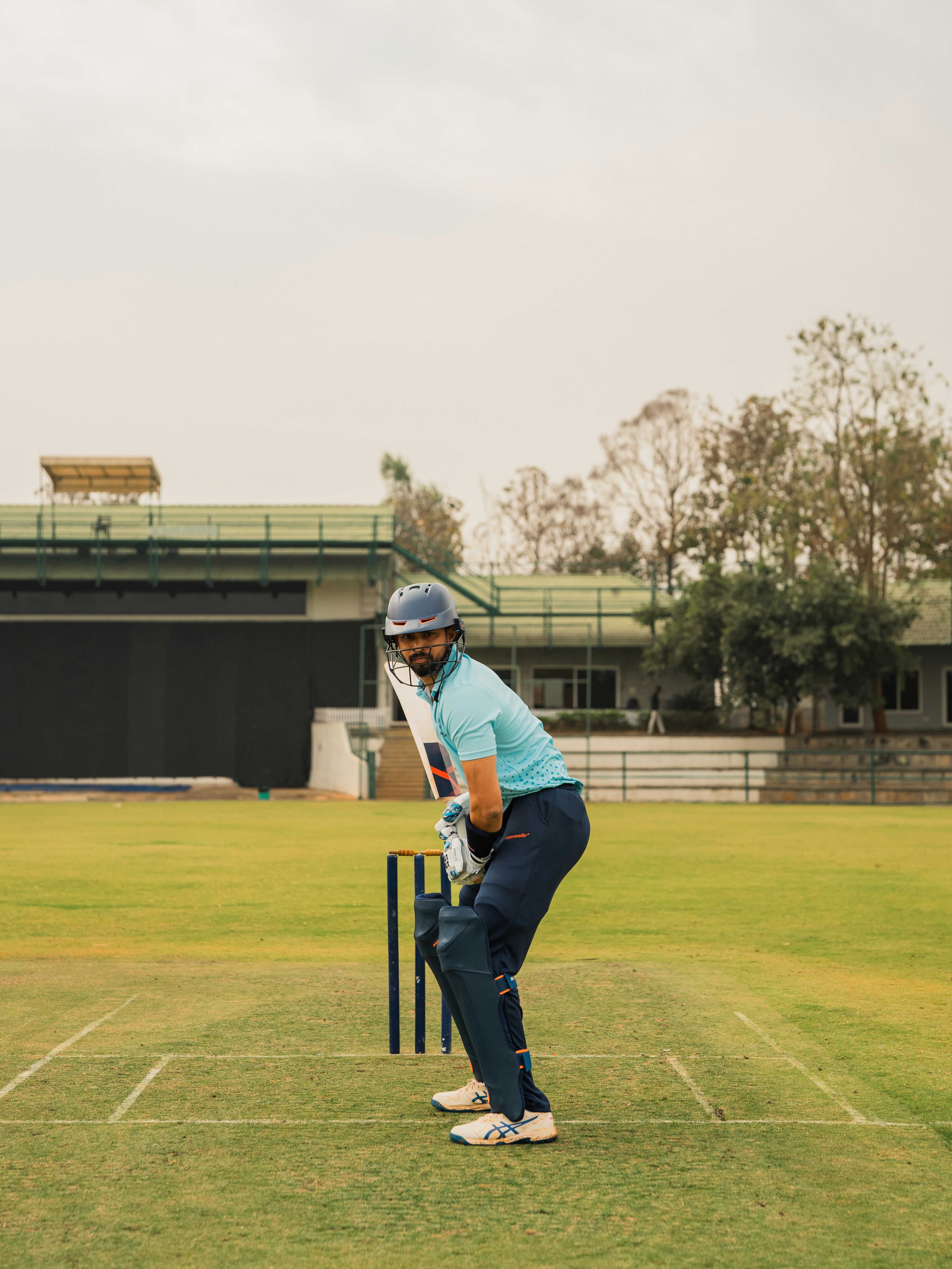 A man in cricket gear batting on a green field.