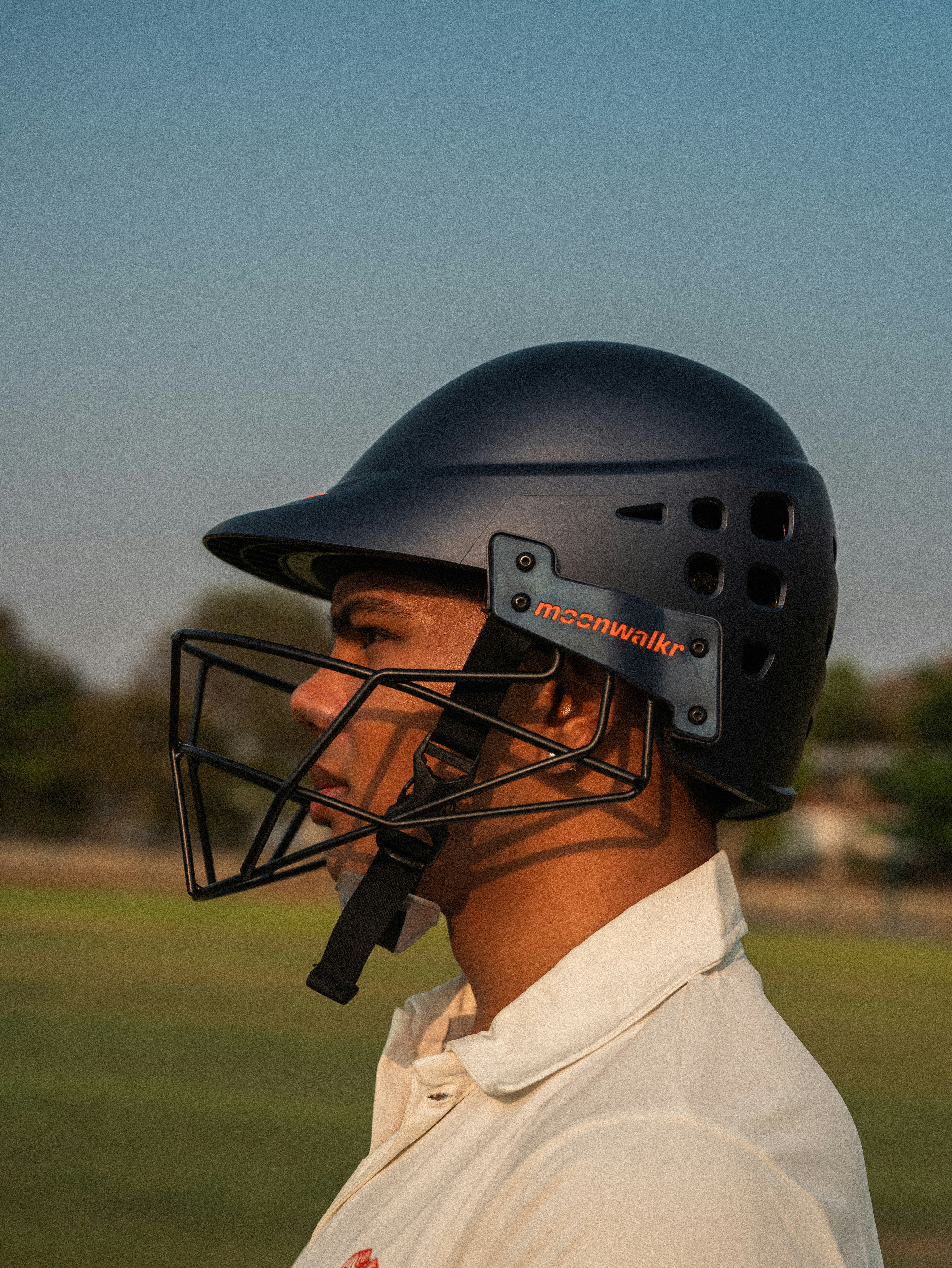 Side-profile of a baseball catcher in helmet under soft evening light