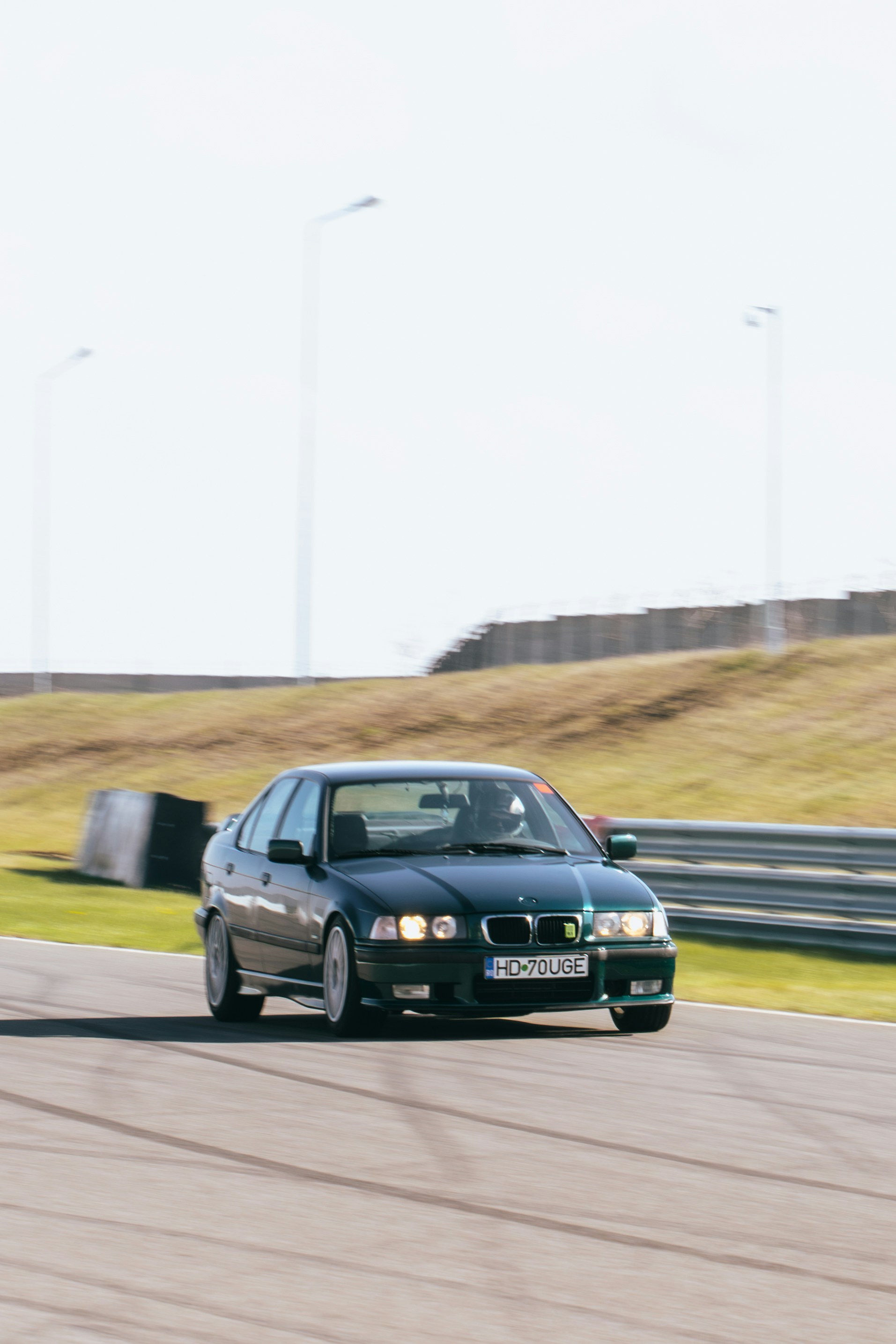 Green BMW sweeps through a sunlit track in motion