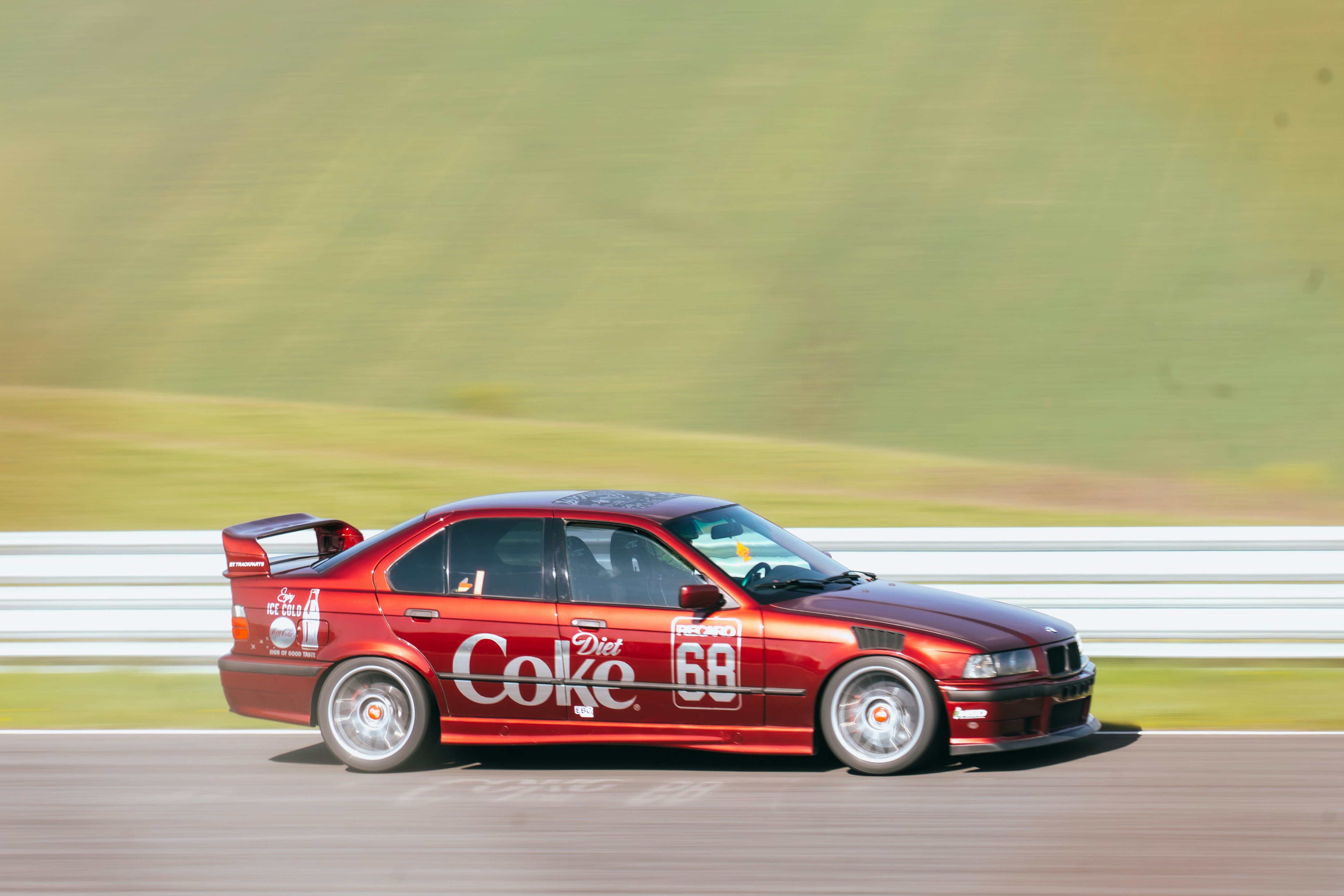Red Coca-Cola race car in motion on track with blurred background