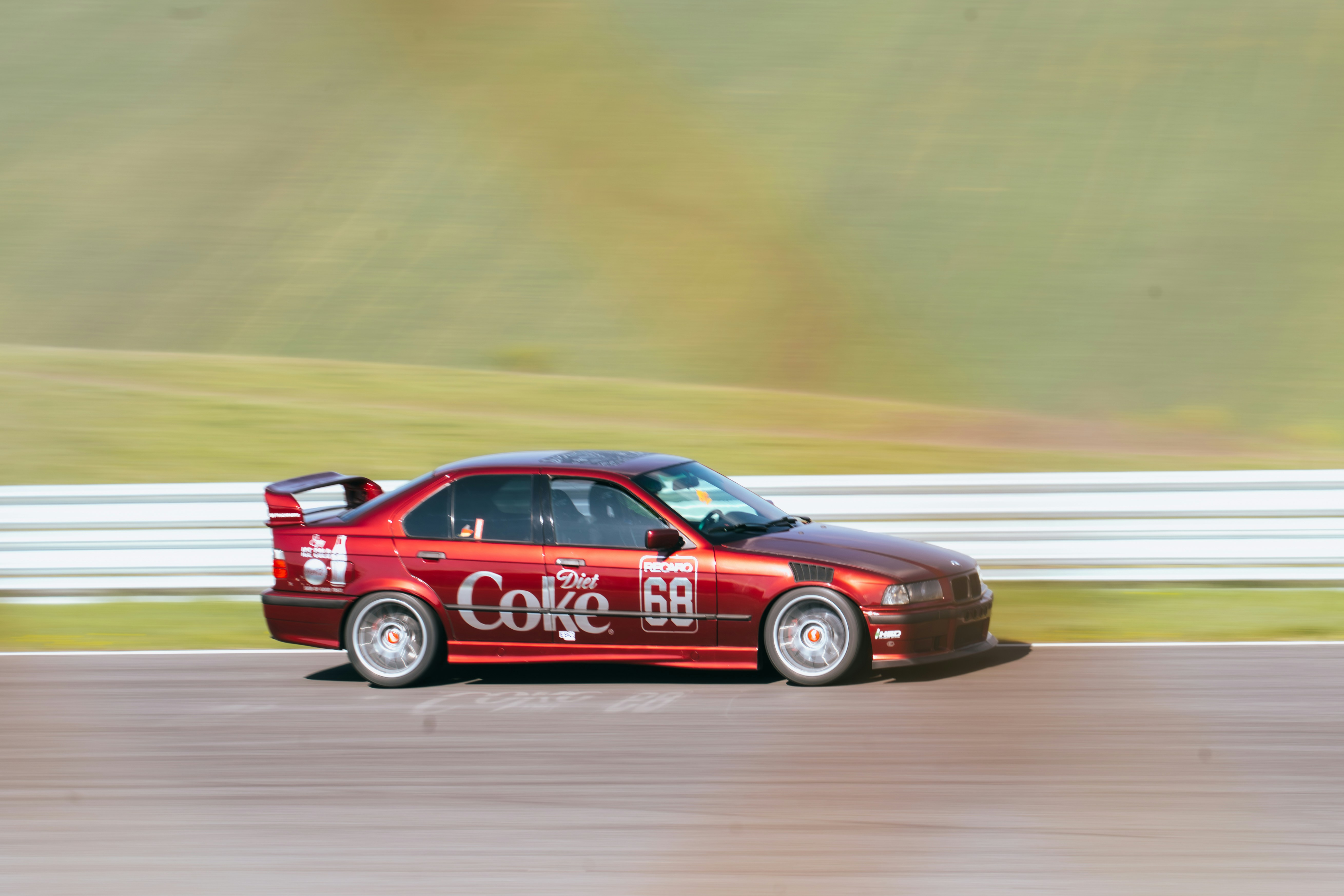 Coke-Livered Blur: Red Racing Car in Motion on a Track