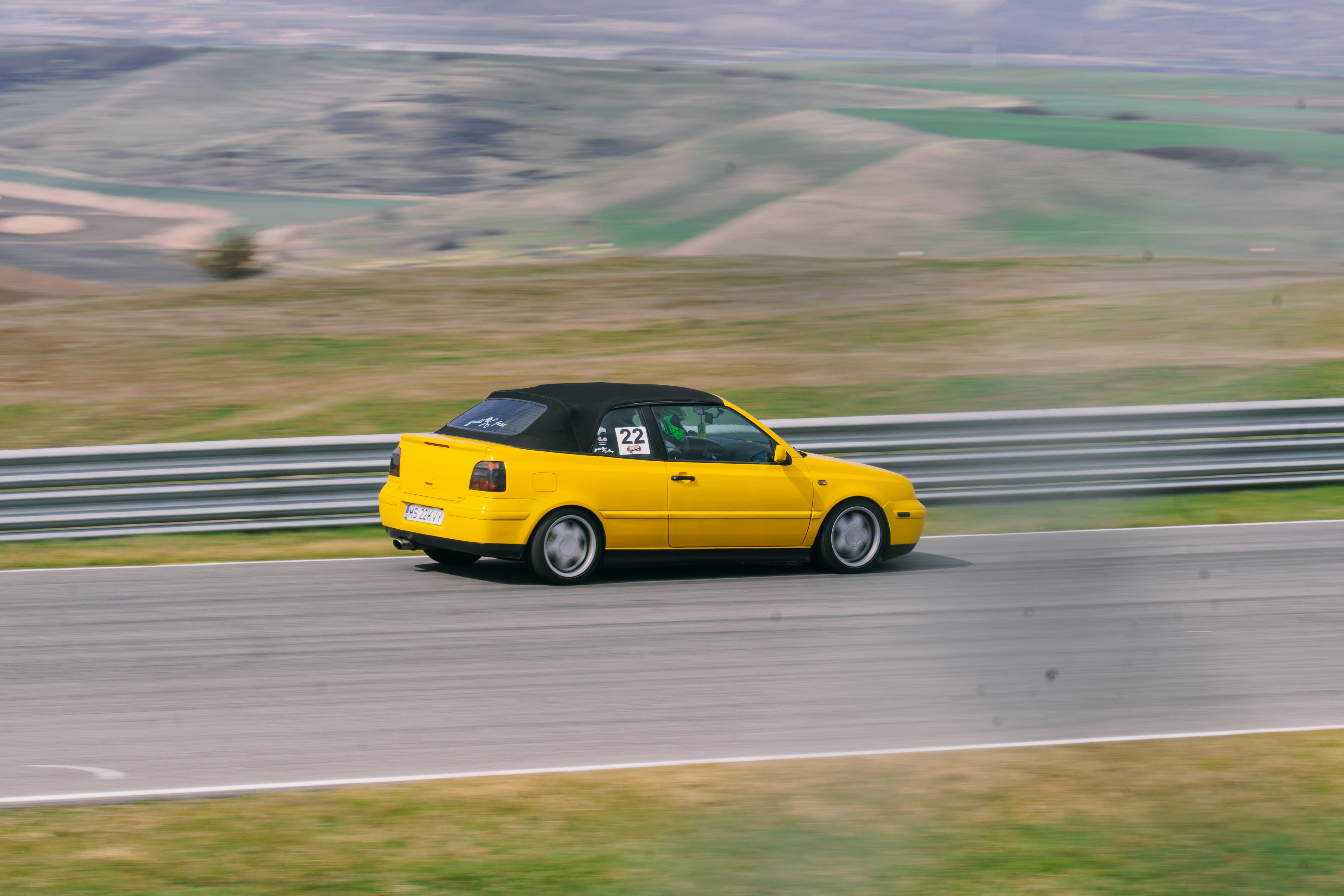 Yellow racer carving the countryside on a sunlit track