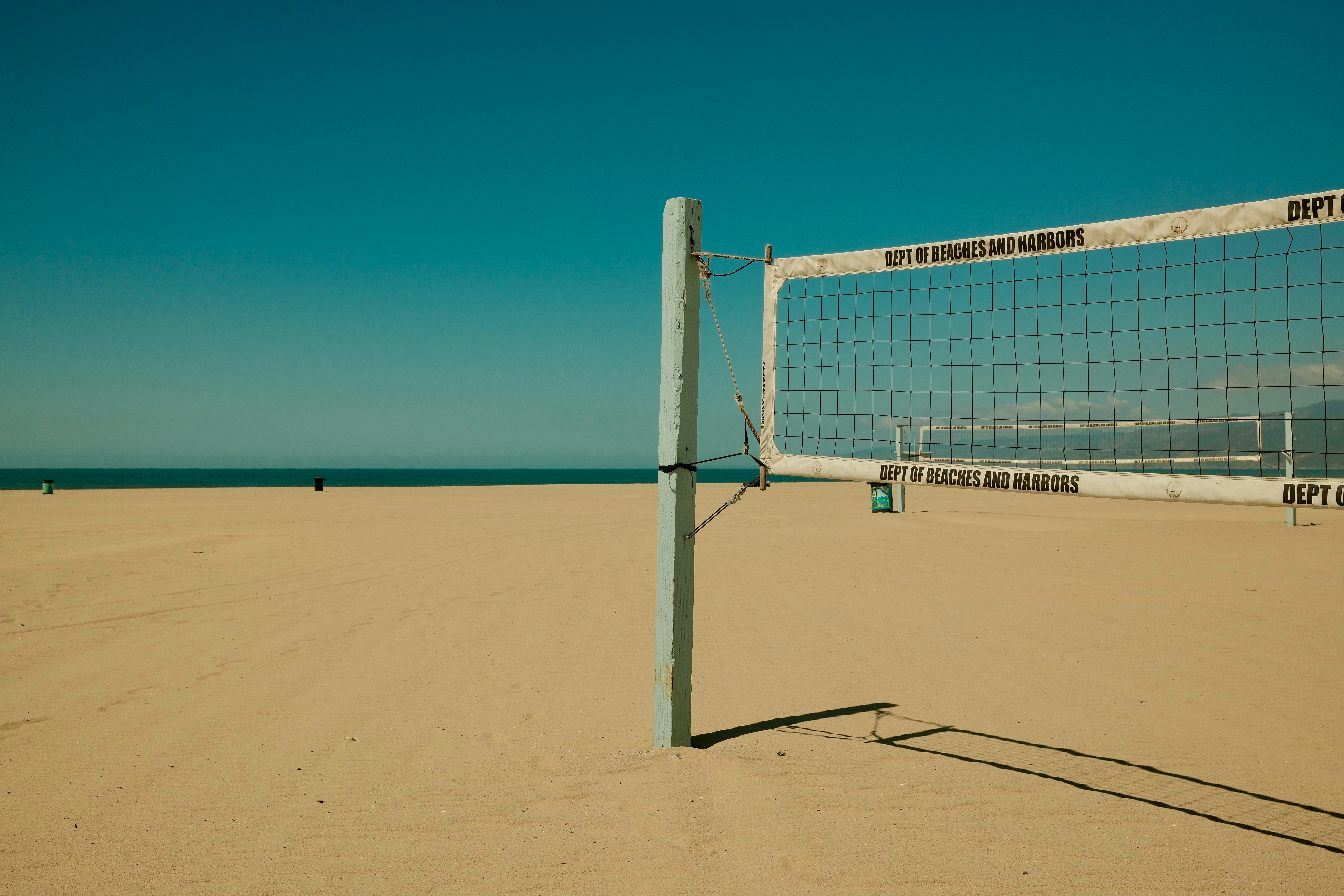 Deserted Beach Volleyball Net Framing a Sunset Horizon