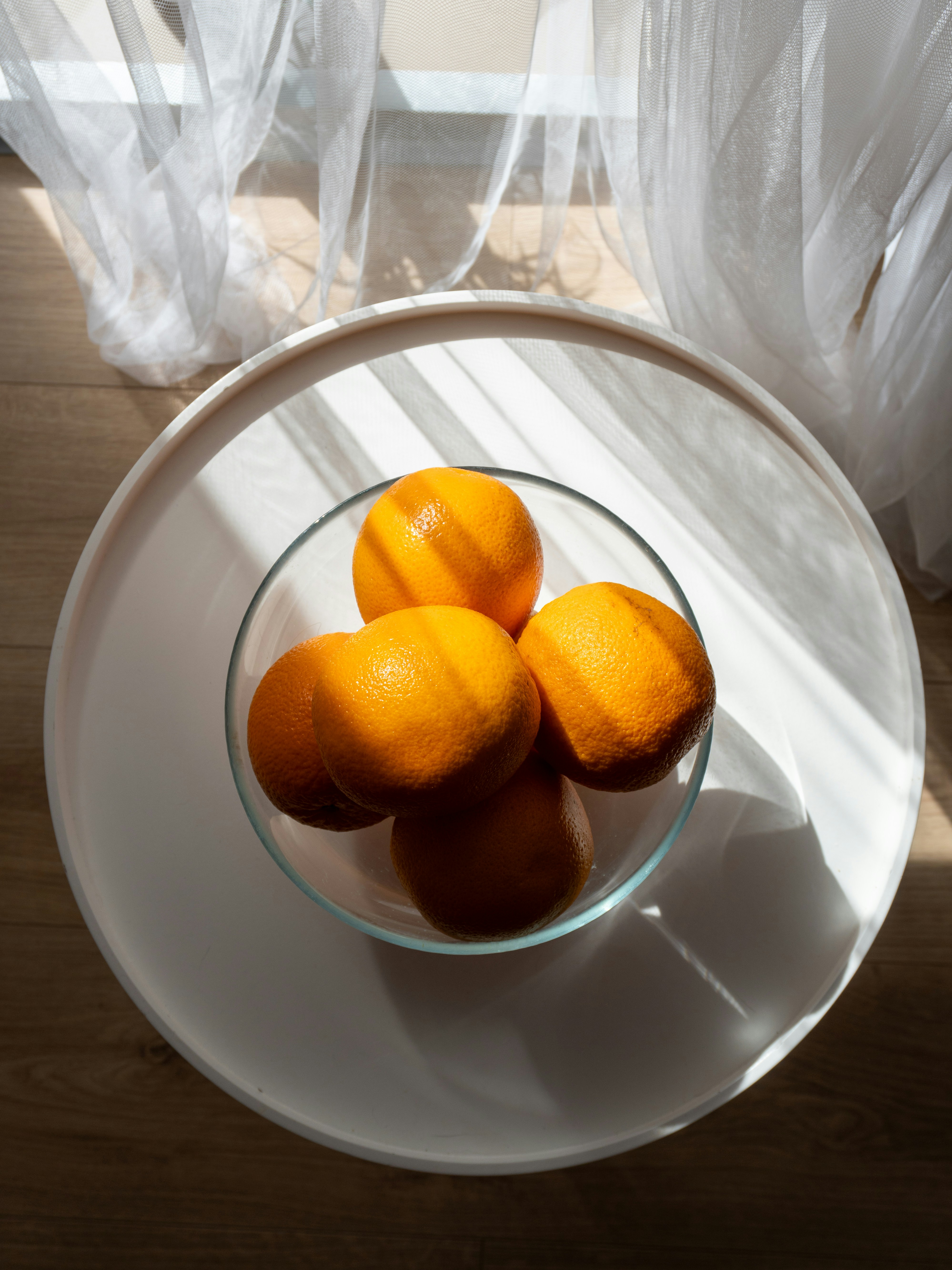 Sunlit Citrus Core: A Glass Bowl of Oranges on a White Tray