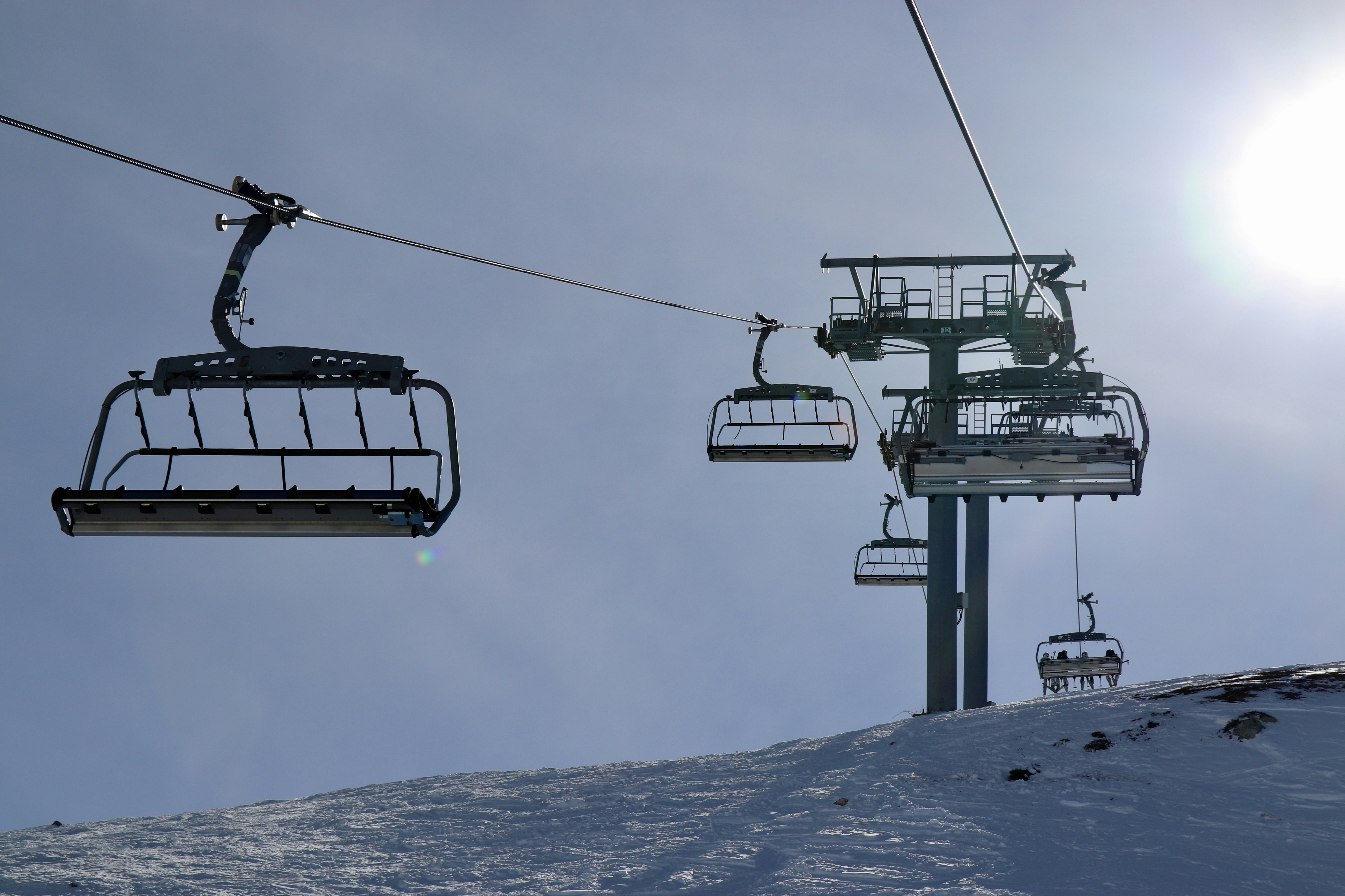  Glacier Lift at Noon: Empty Chairs Hover Over a Snowy Peak