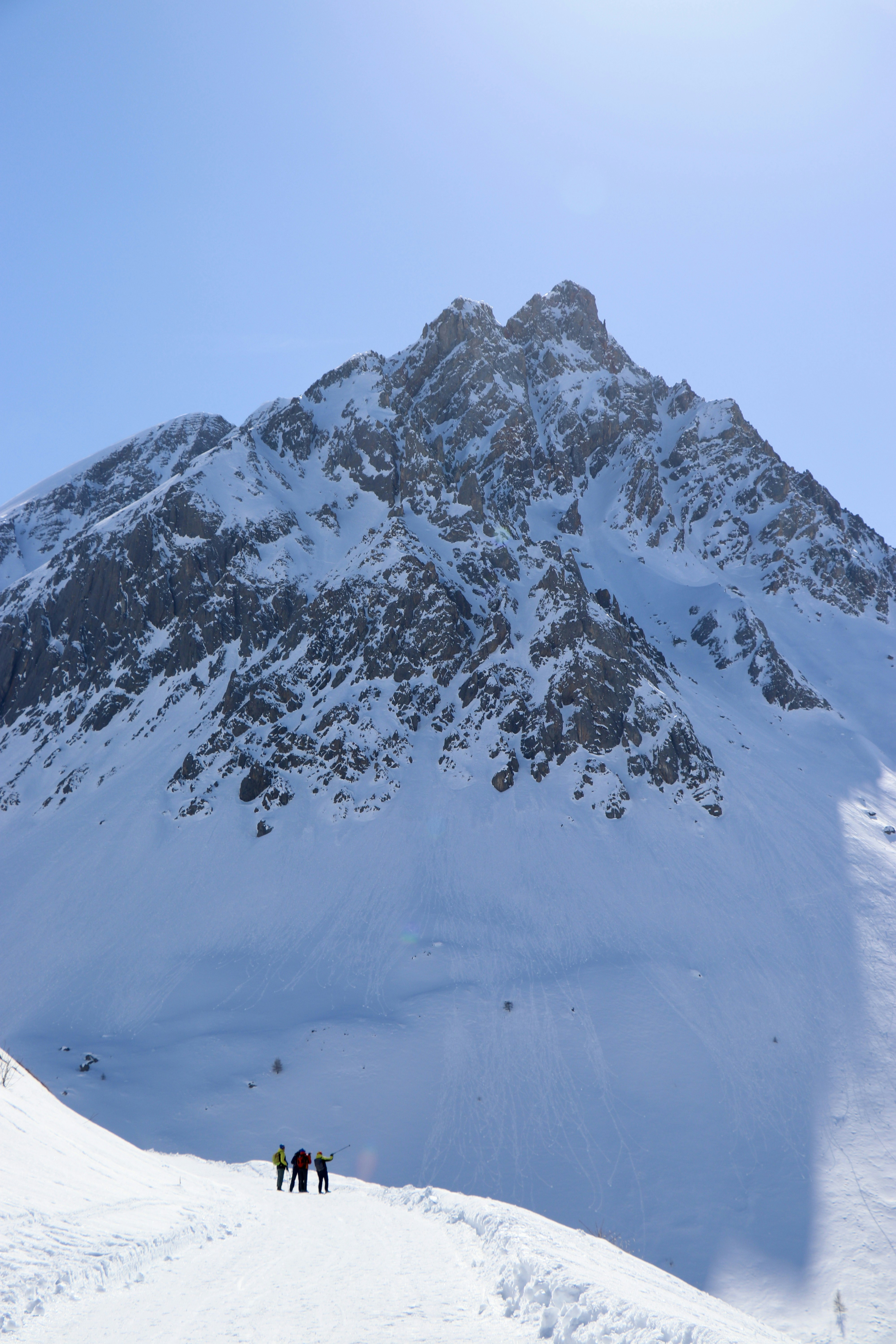 Snowbound Summit: A Triad of Climber Silhouettes Under a Jagged Peak