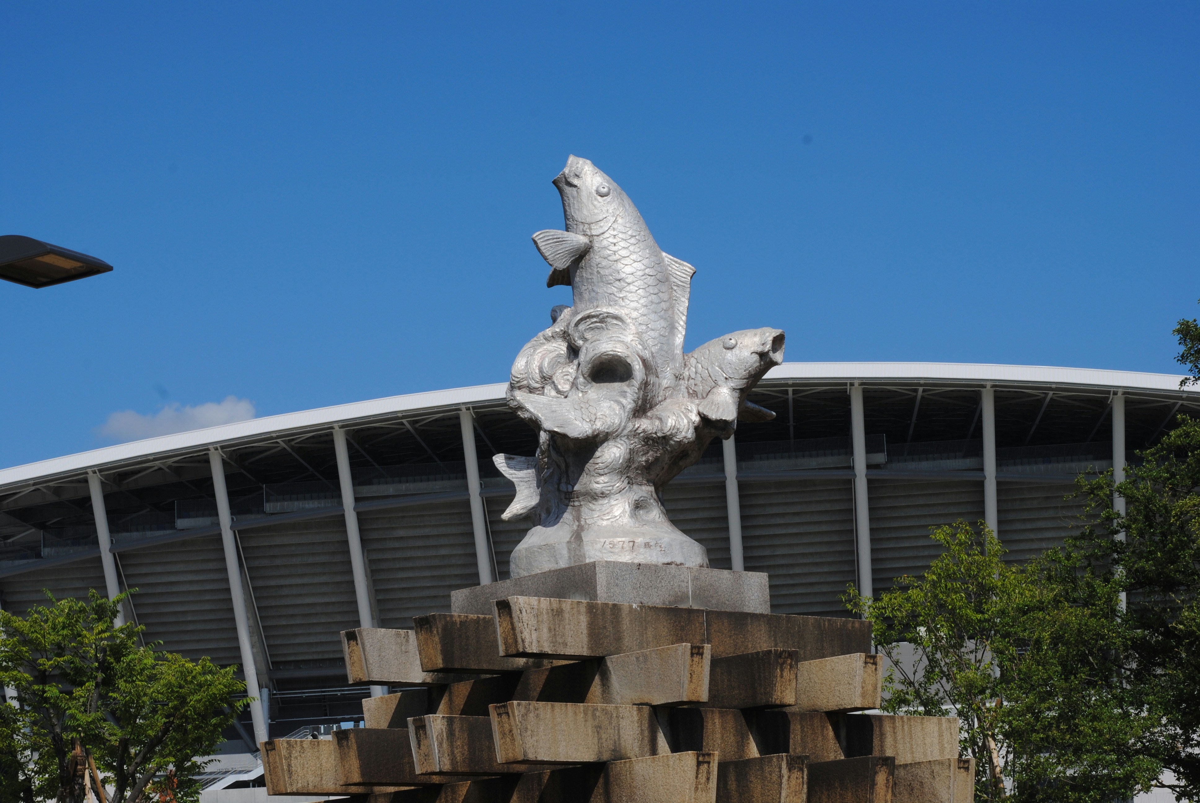 Kinetic Fish Monument Rising from Stacked Blocks