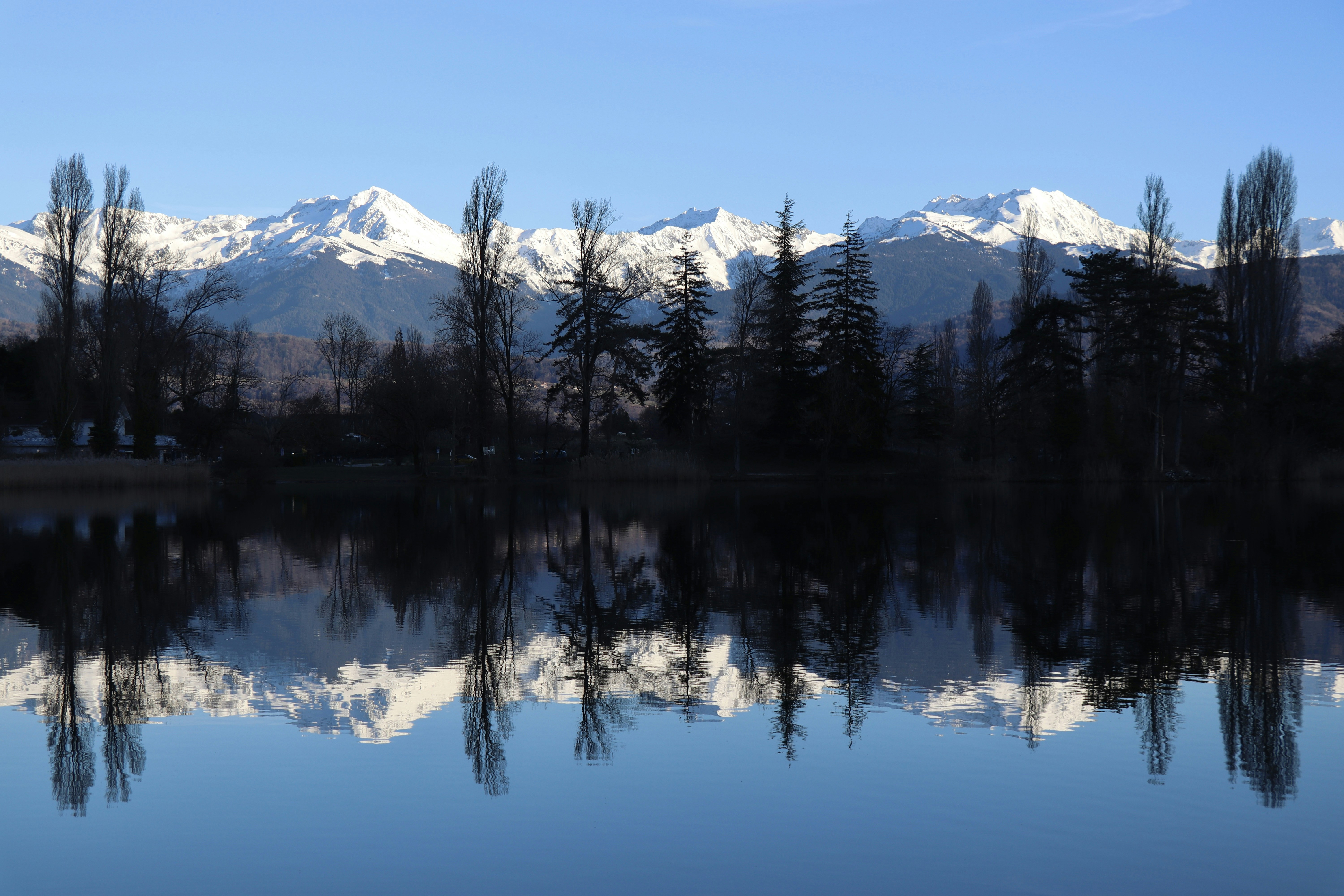 Snow-kissed ridge mirrored: mountains at dawn over still water