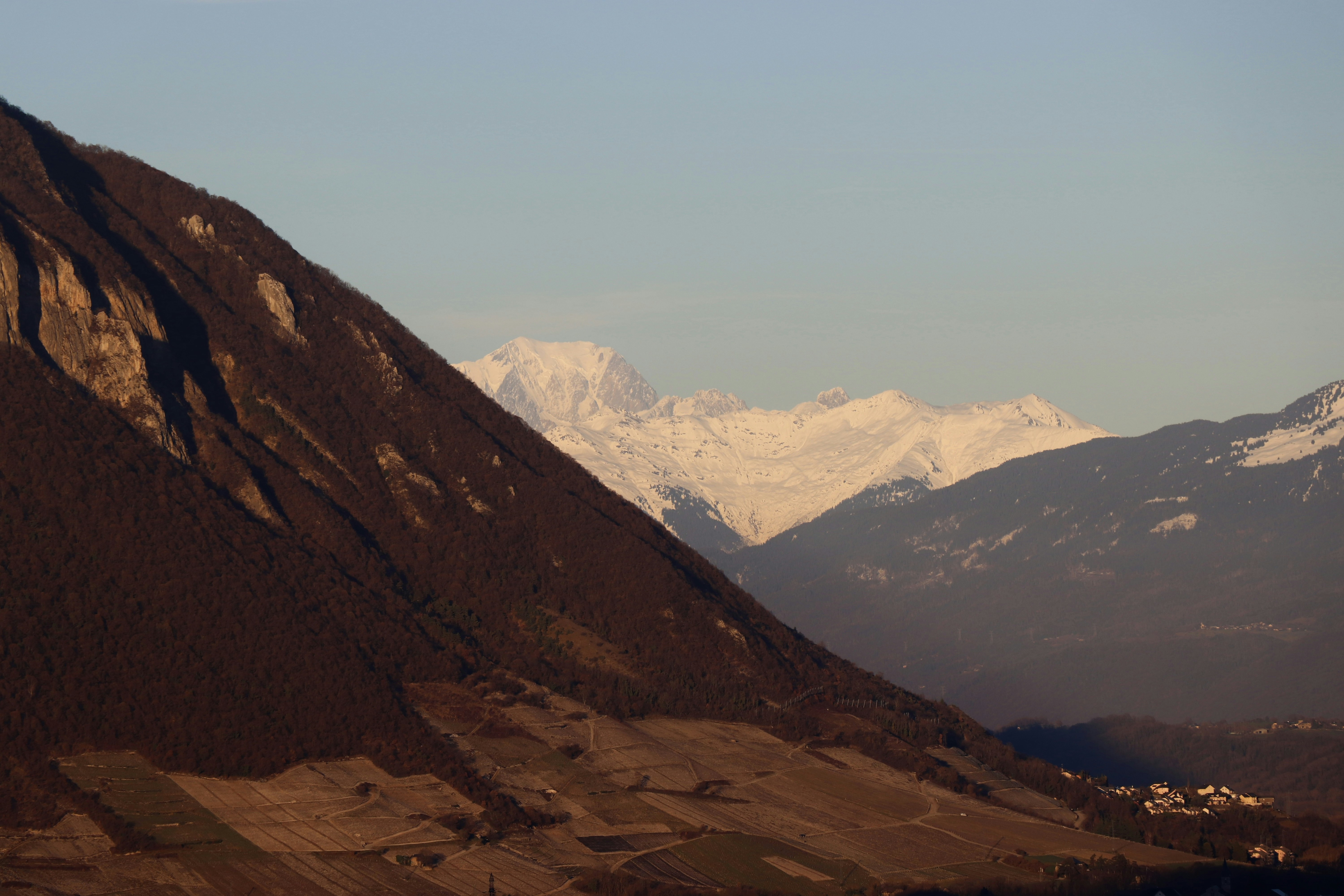 Snow and shadow: distant peaks glow above a terraced valley