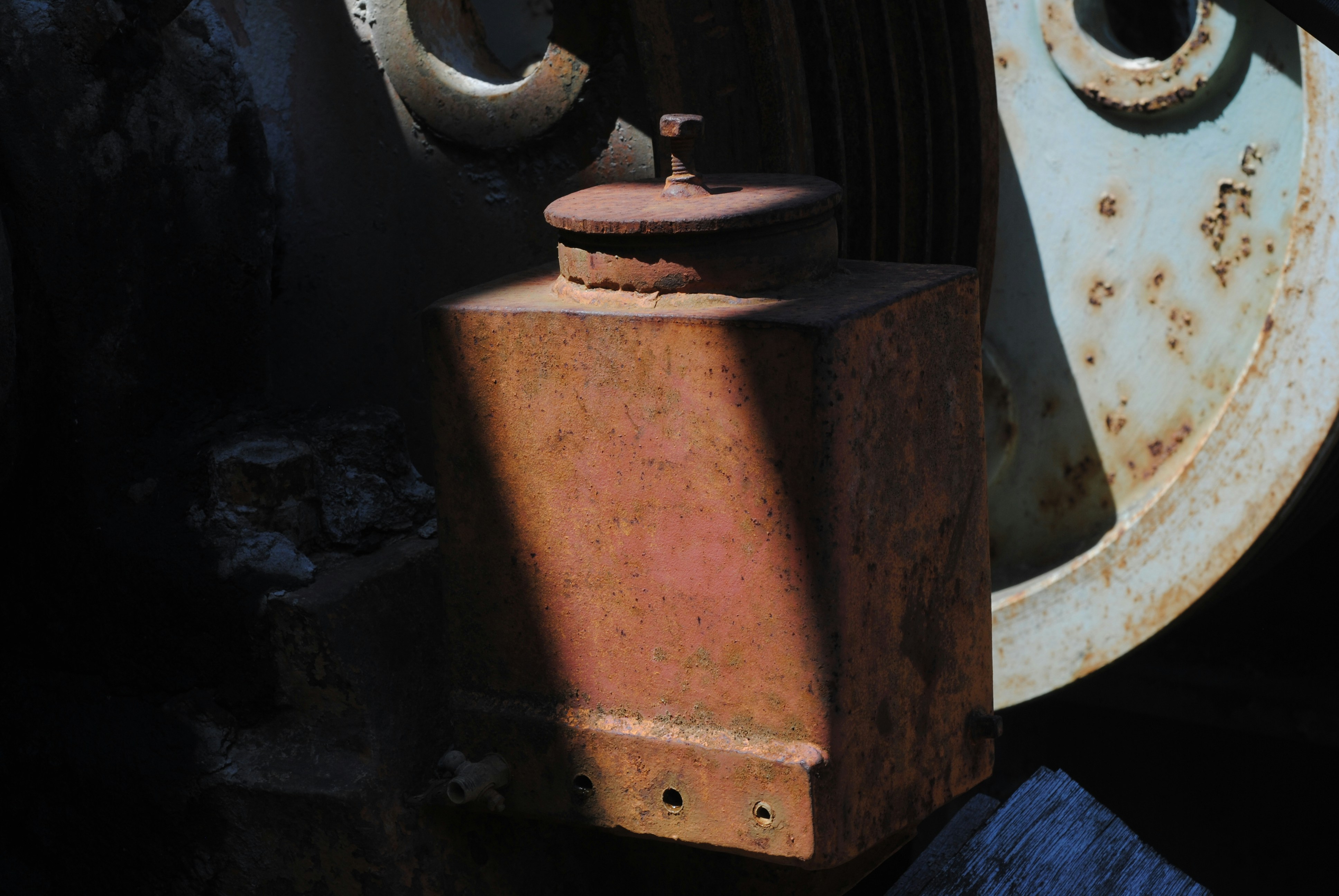 Rusted Core: a weathered canister amid industrial wheel shadows