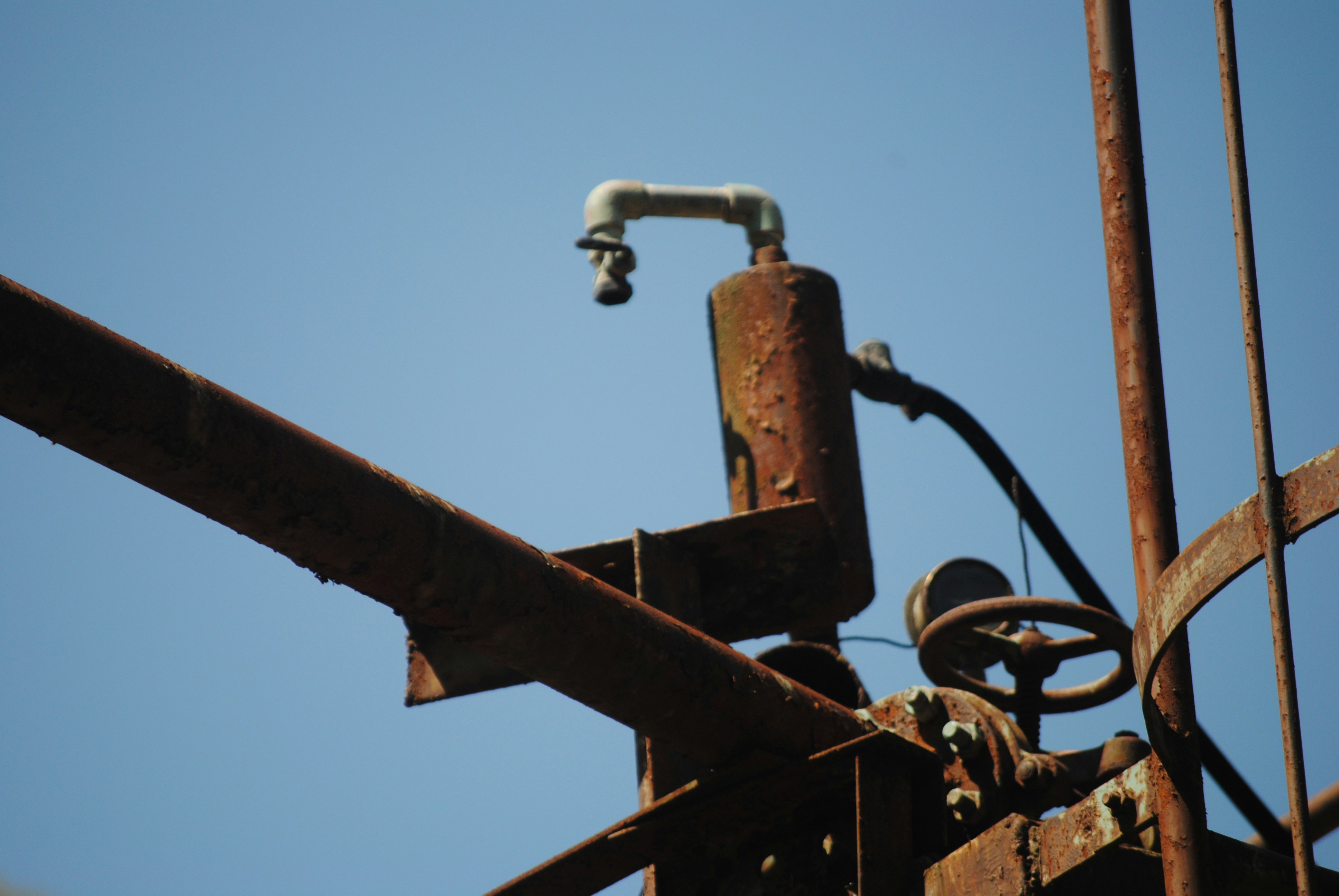 Rusty conduit sculpture against a clear blue sky