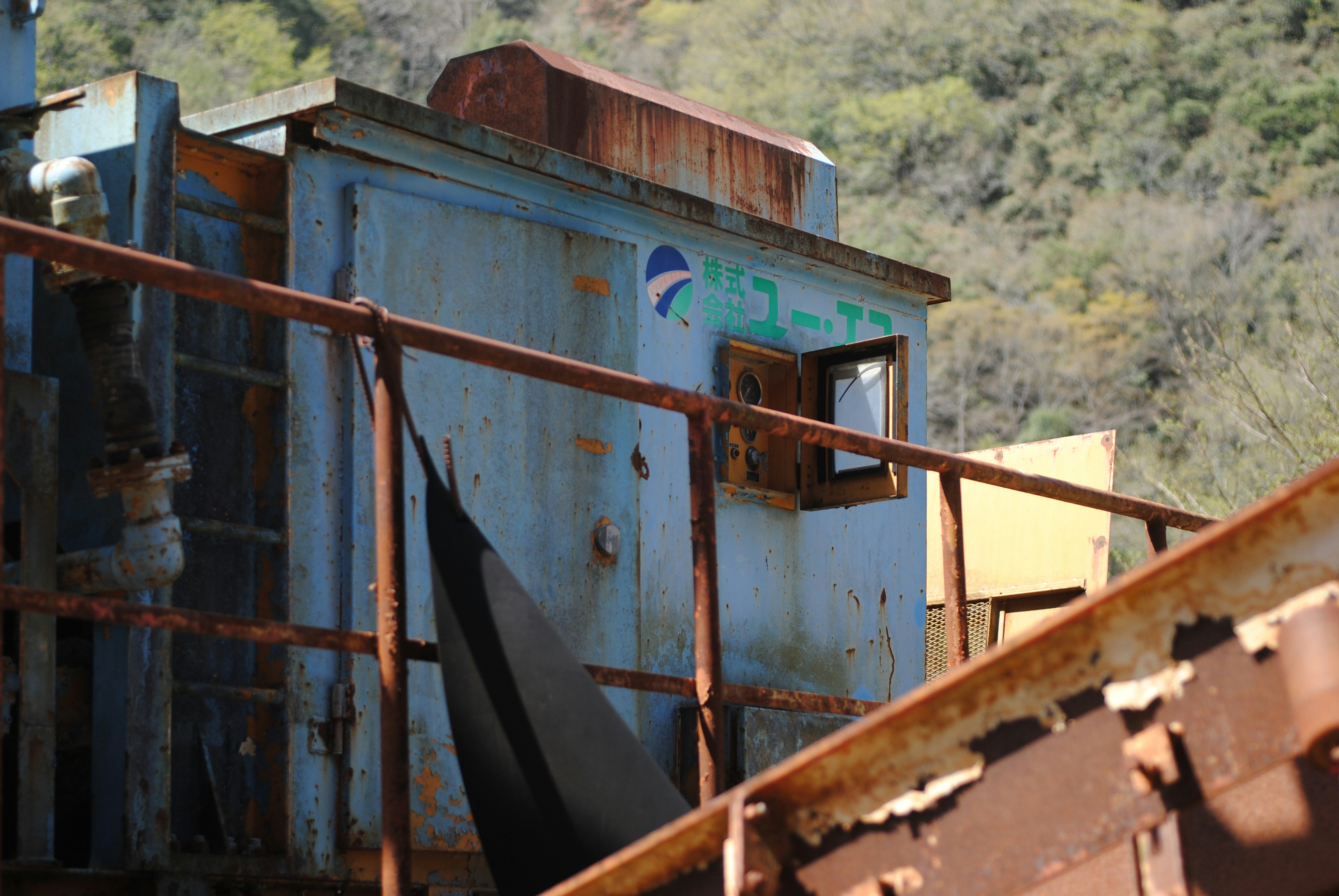 Rusty Machinery and Weathered Blue Structure in an Industrial Yard