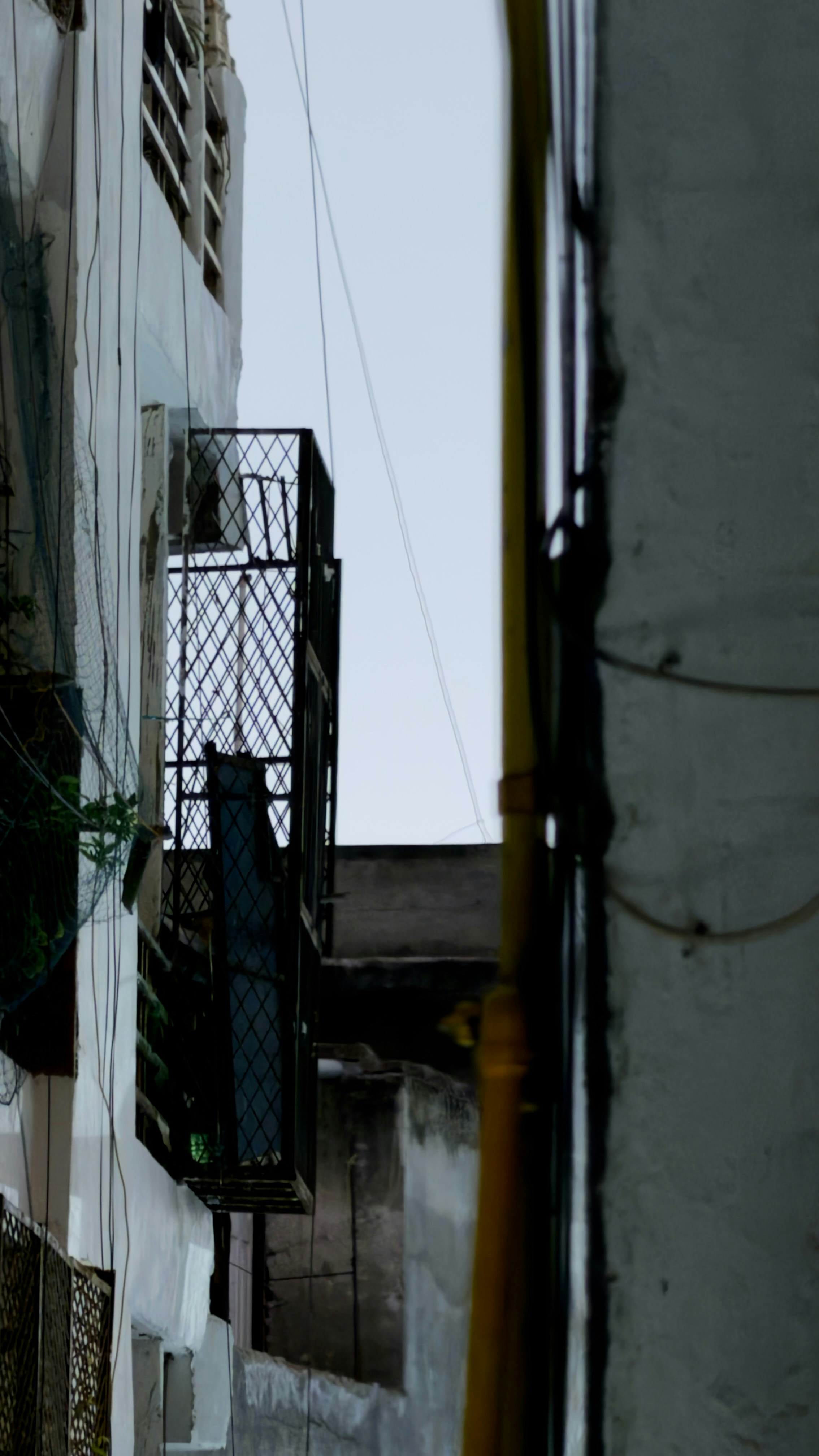 Narrow City Alley: A Balcony Climb Between Wires and Walls