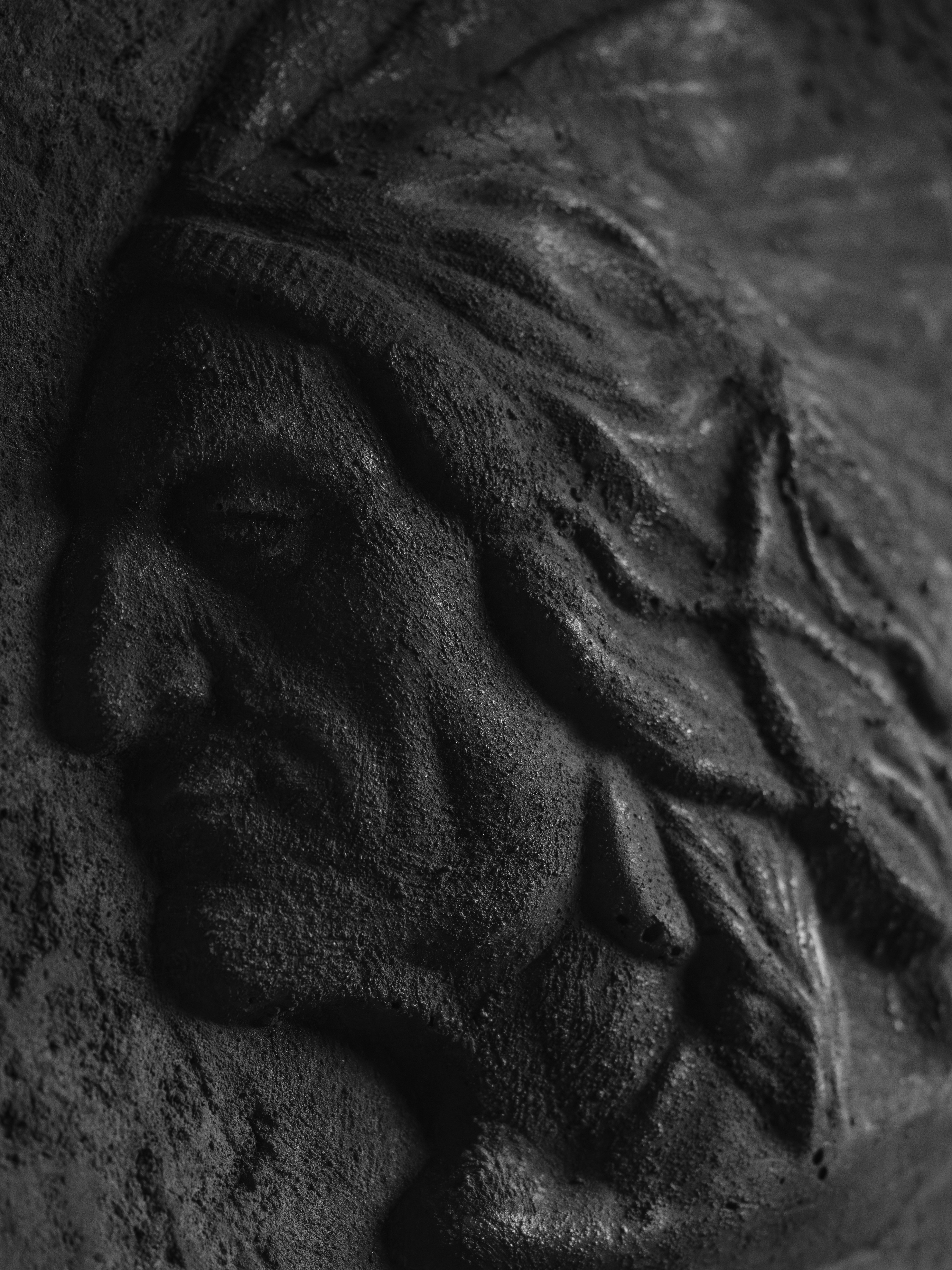 Stone Portrait in Shadow: A Weathered Face Emerges from the Surface