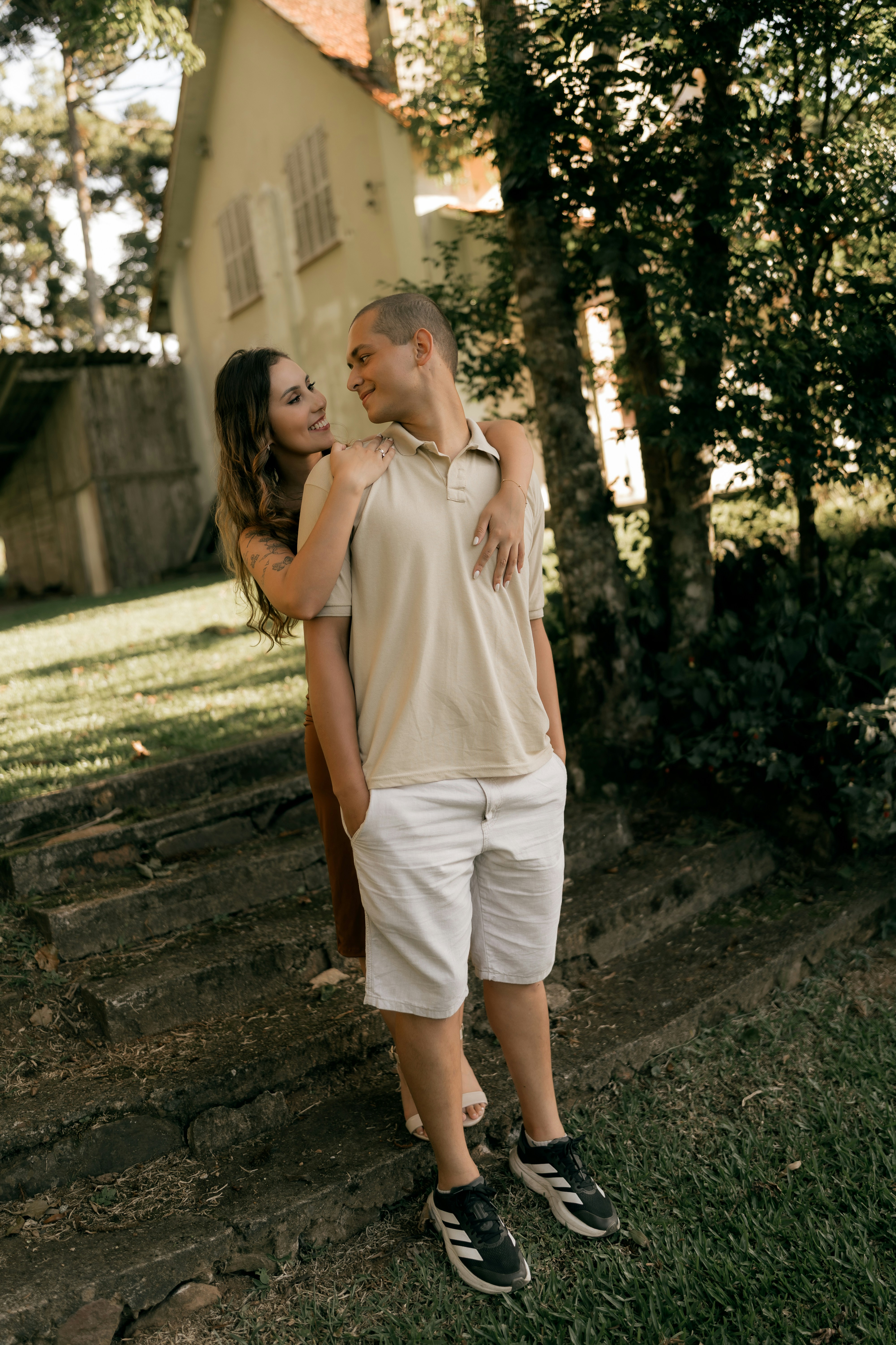 Couple in a sunlit yard share a warm moment on stepped stone stairs