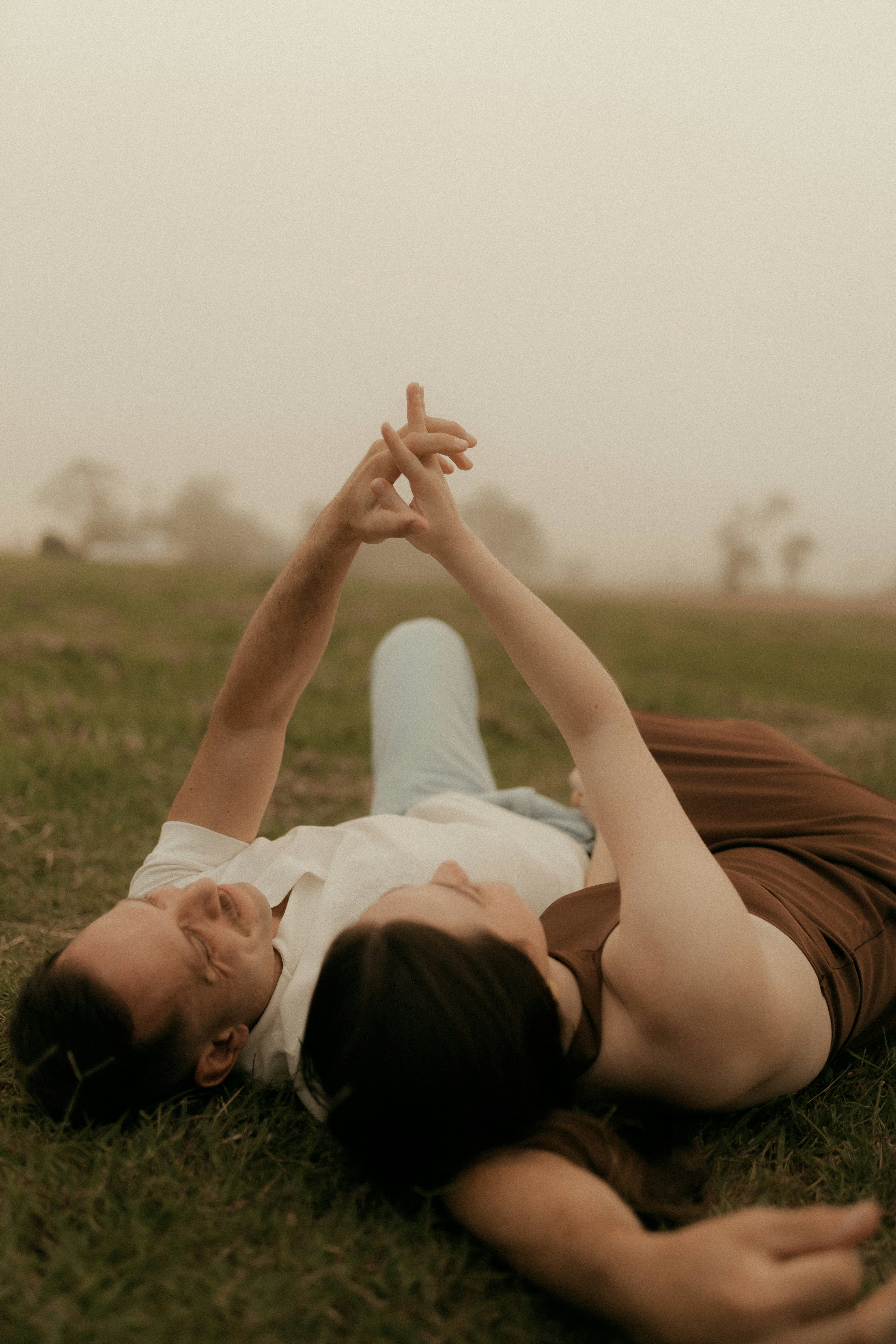 Hands Linked, Eyes to the Horizon: A Quiet Moment on the Grass
