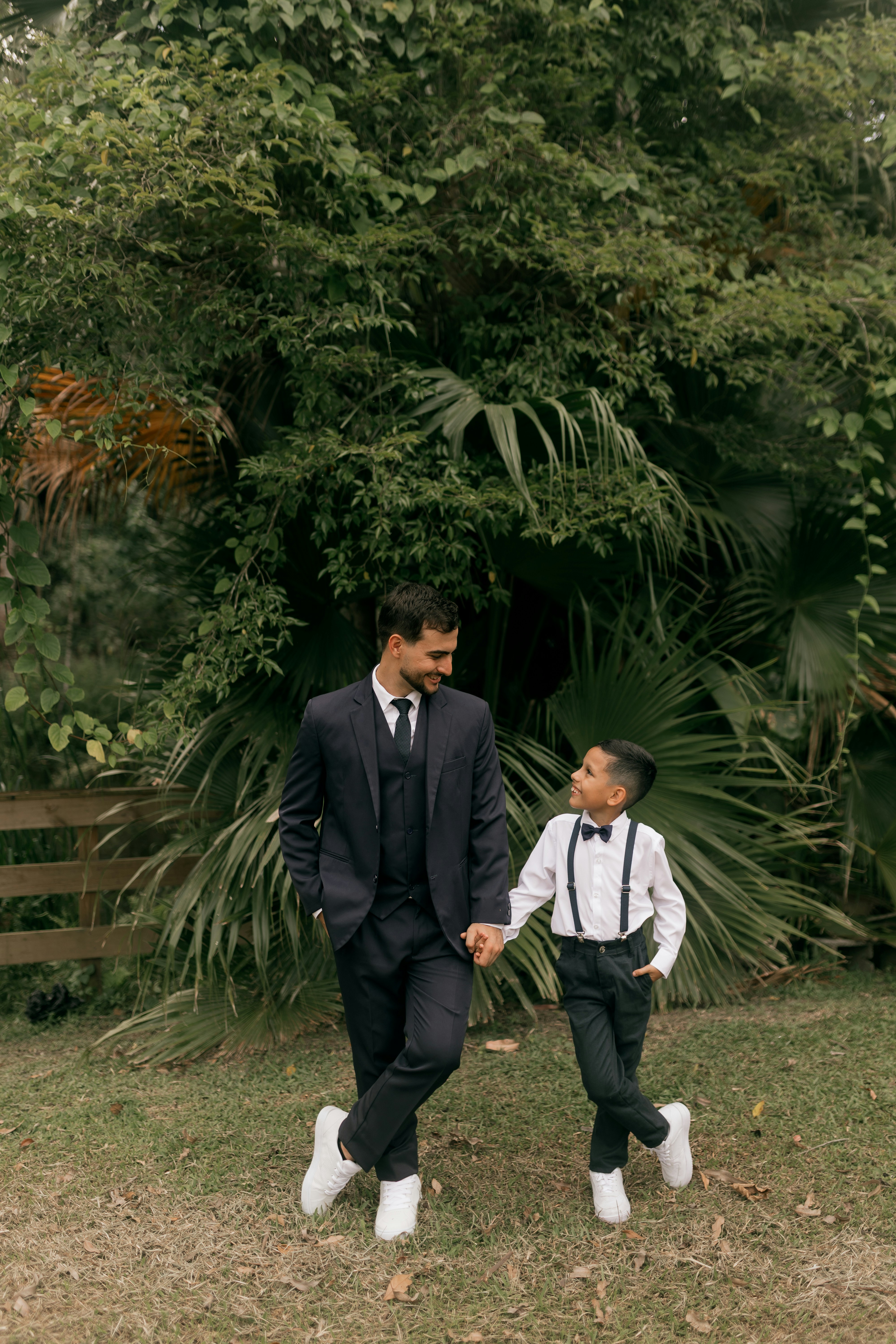 Man and boy in suits holding hands outdoors