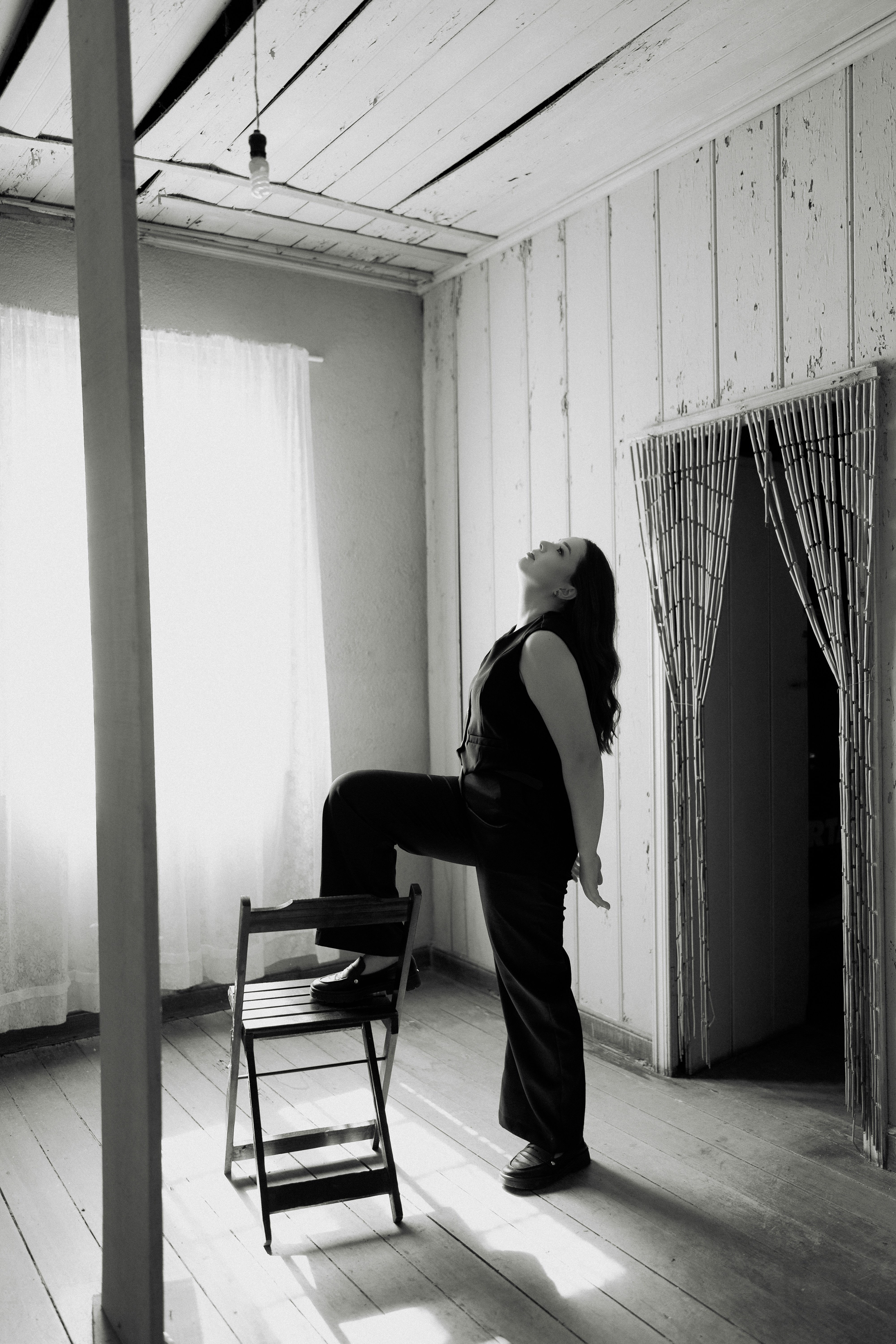 Contemplative ascent: a dancer poised between chair and doorway