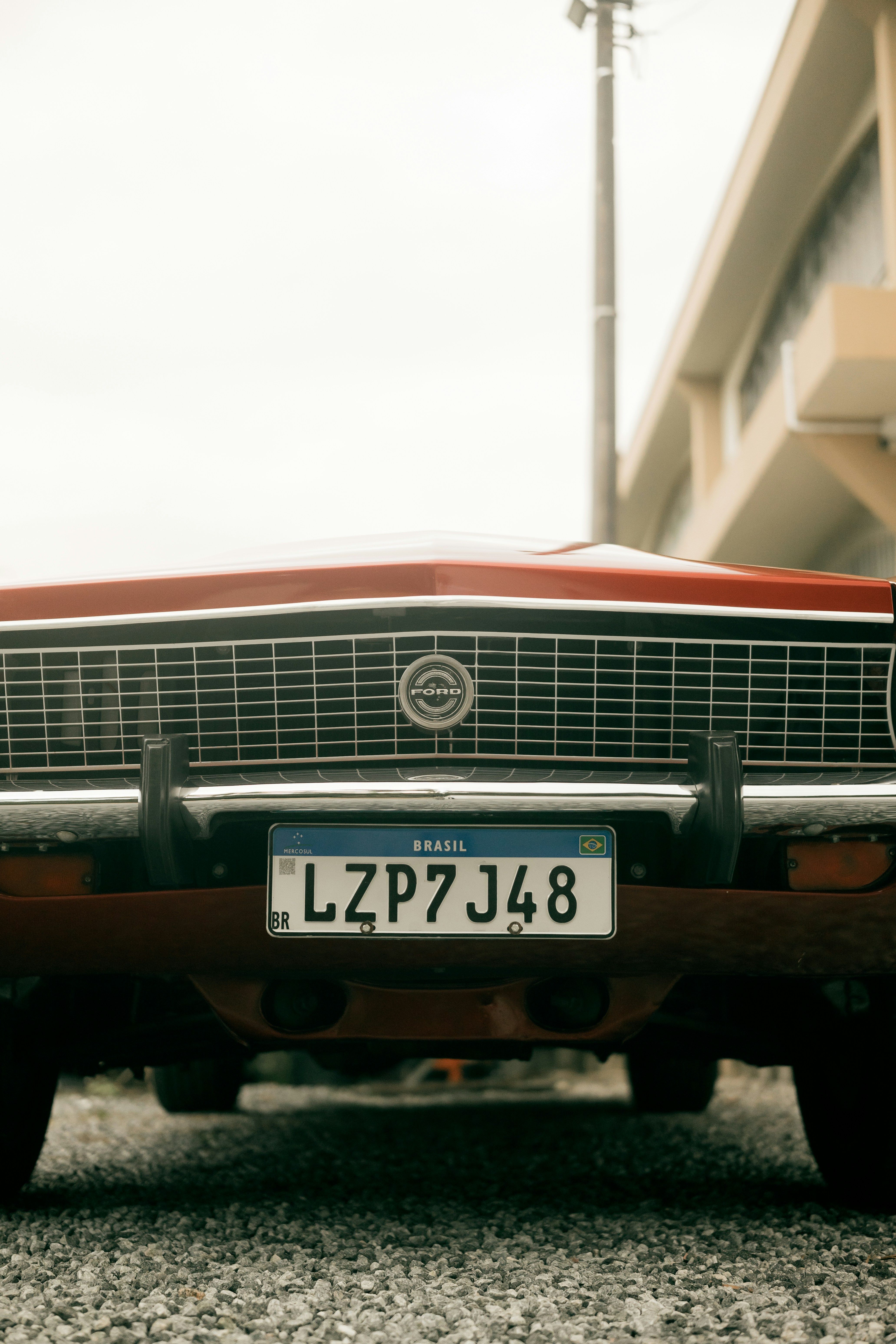 Vintage Ford Grille Beyond the Hood: A Brazilian Plate Obscured by Rust and Road