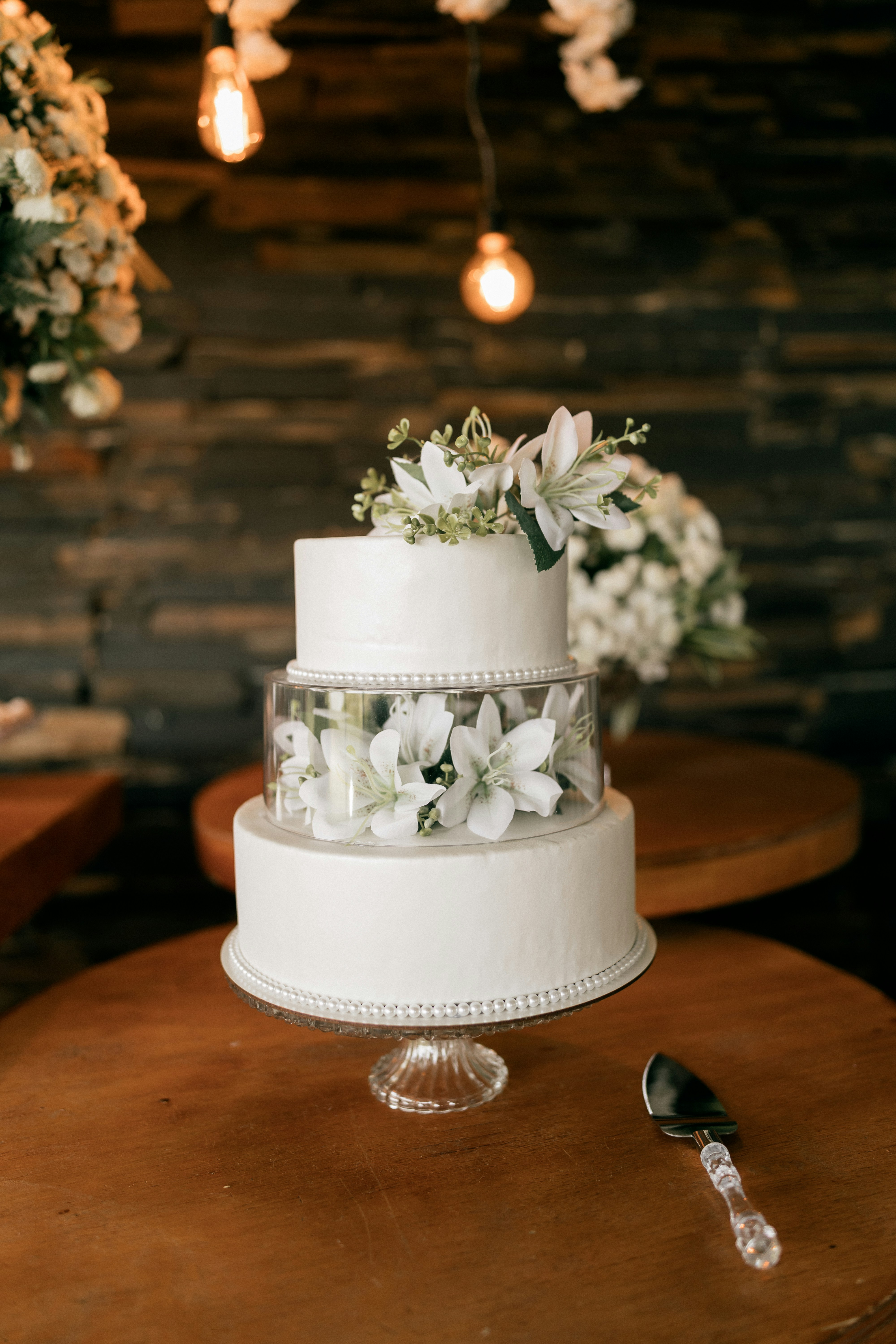 Tiered Elegance: A White Floral Cake Under Warm Edison Lights