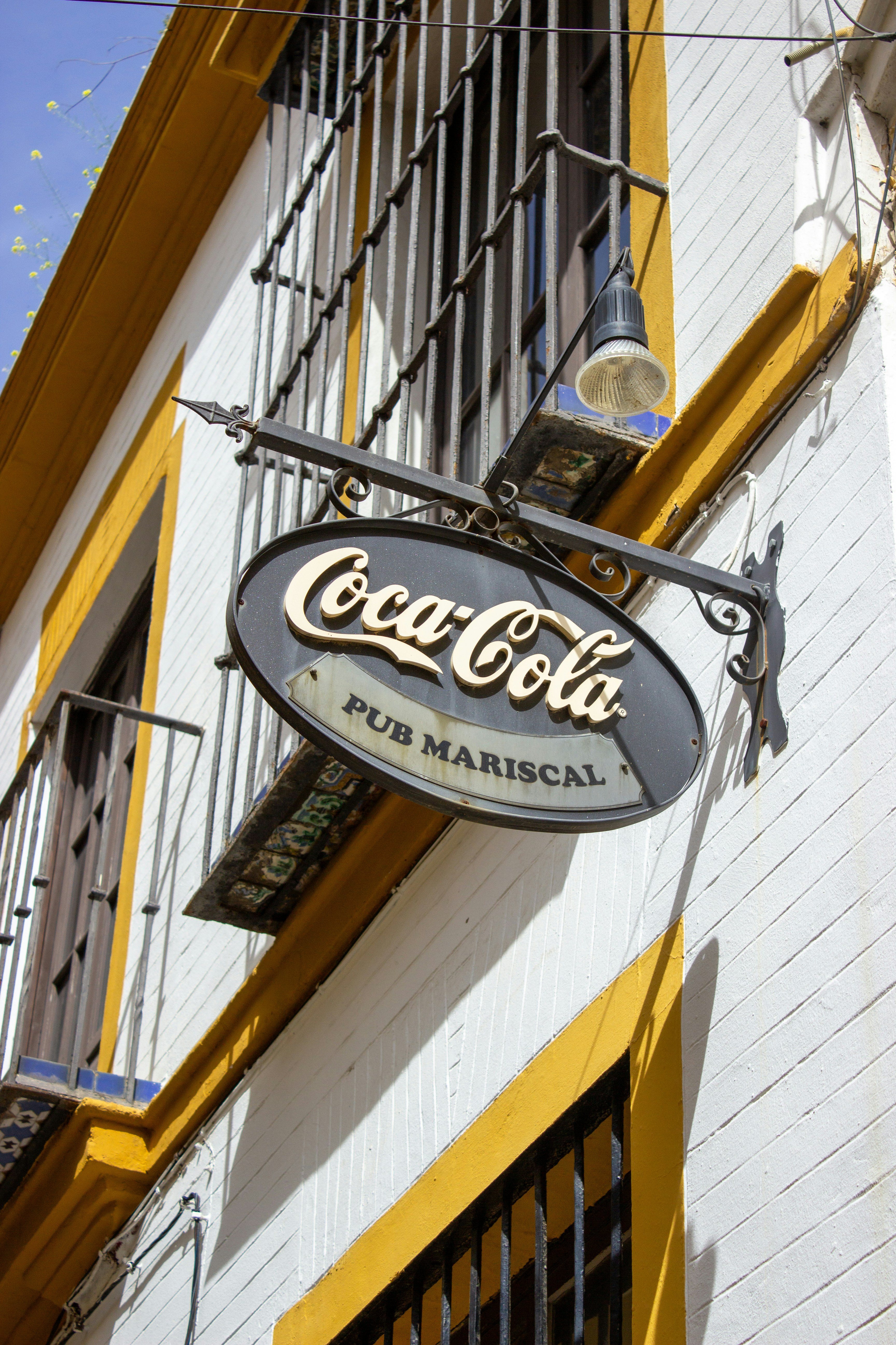 Coca-Cola Sign Adrift on a Sunlit Colonial Facade