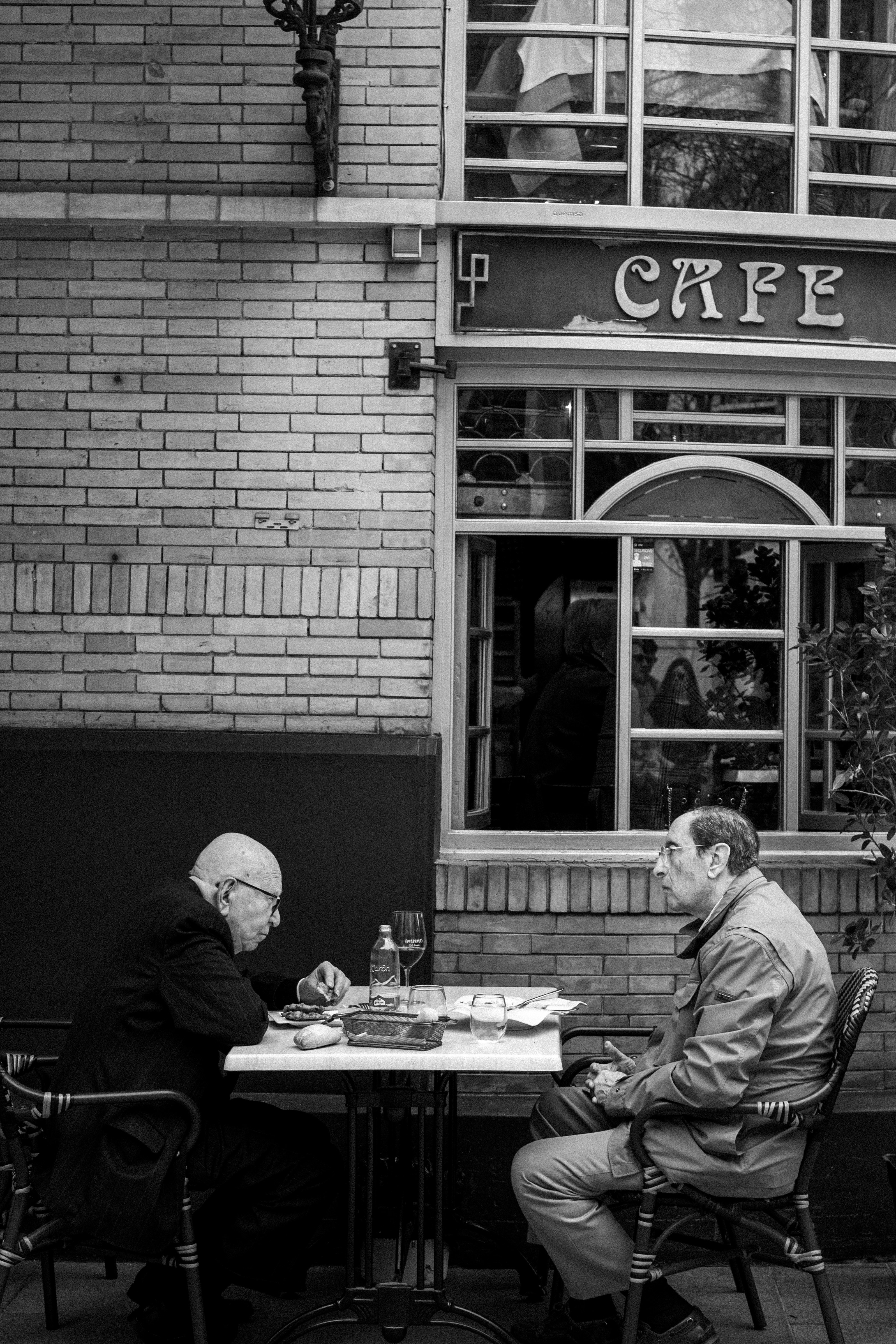 Quiet Café Dialogue: Two Patrons in a Street-Side Moment