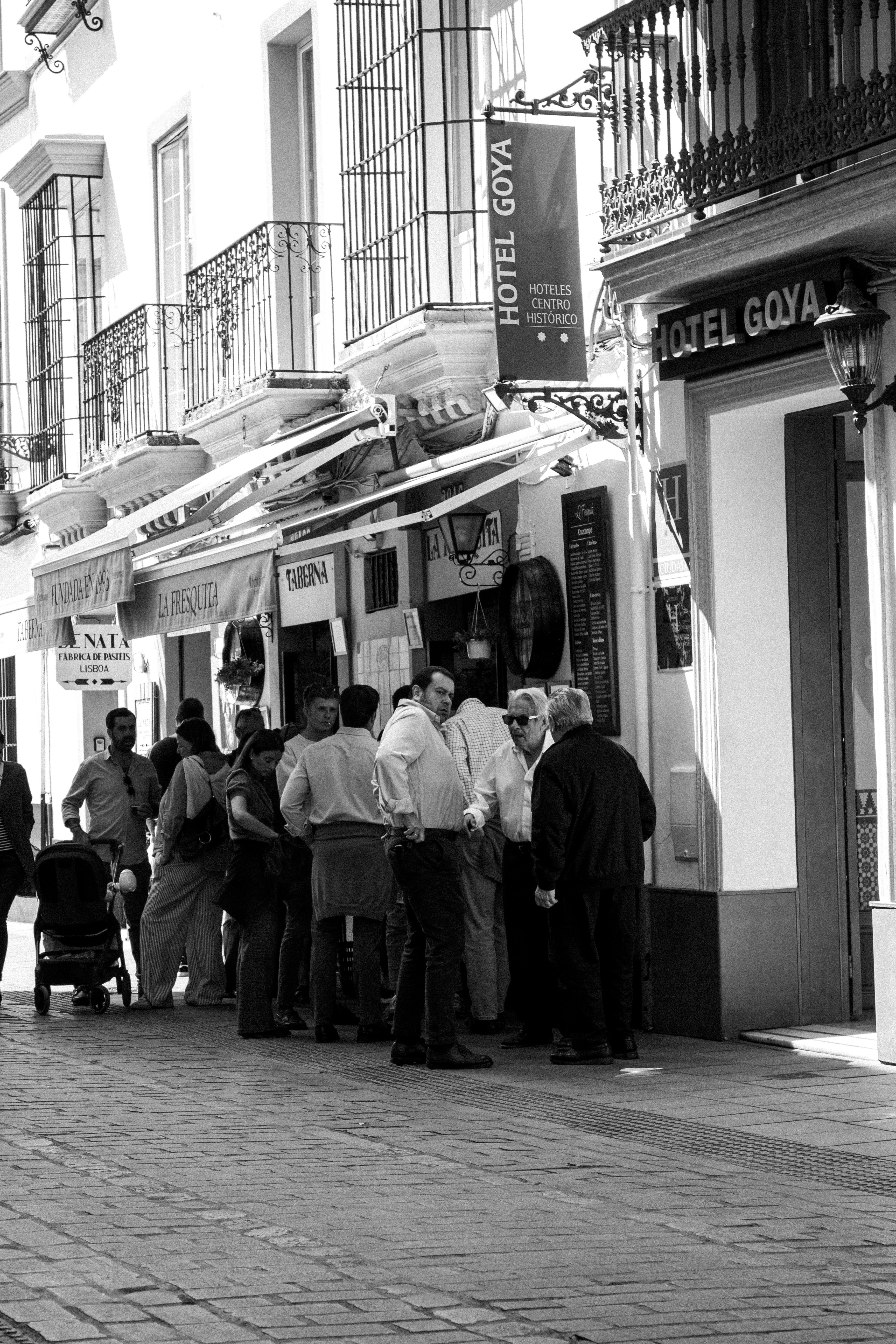 Crowd in front of Hotel Goya on a sunlit Andalusian street