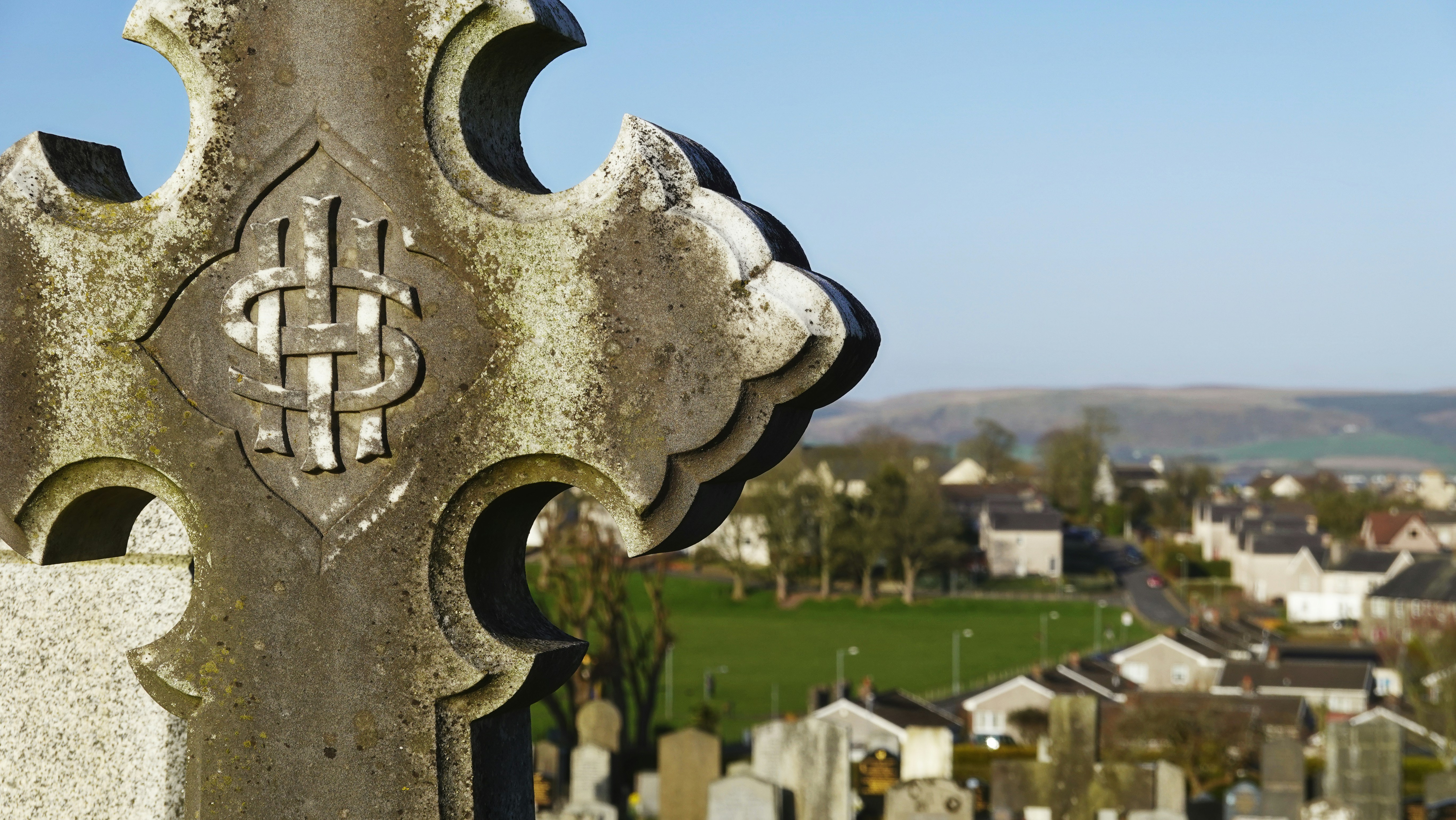 Weathered Cross in Focus: A Cemetery Overlook