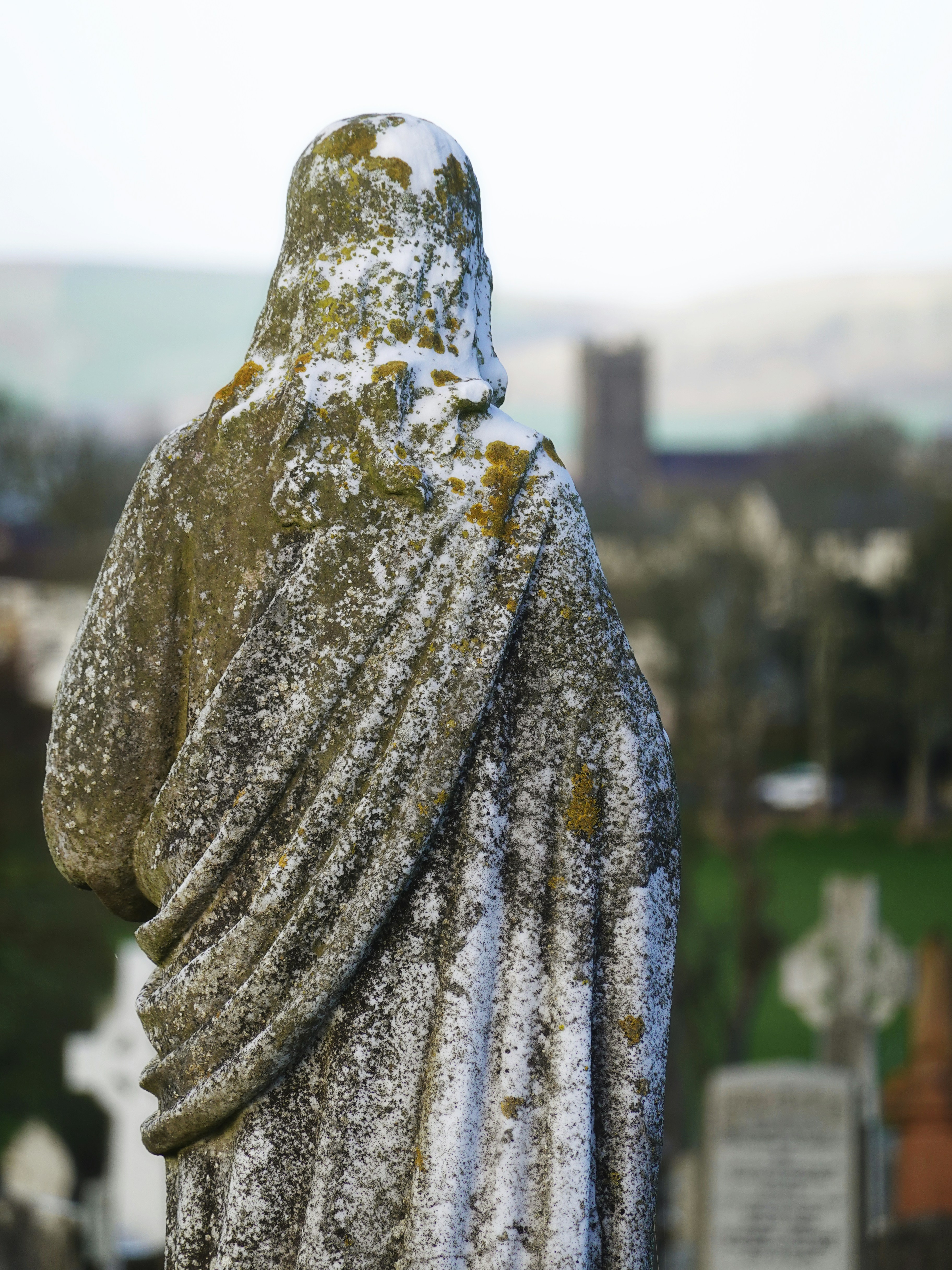 Weathered Cloak: A Stone Figure Watching Over the Cemetery