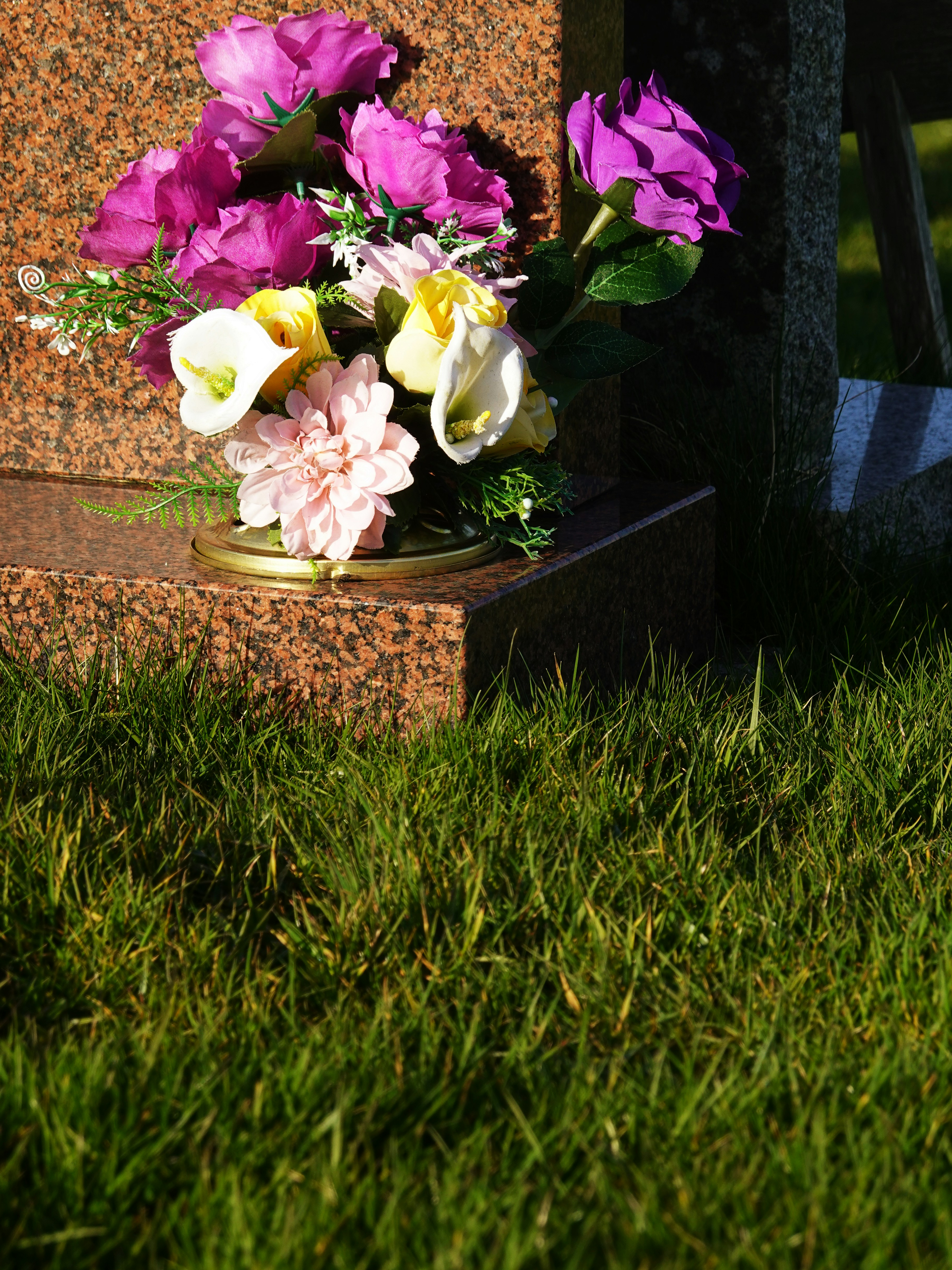 Stone Memorial Bouquet: a sunlit tribute at the graveyard edge