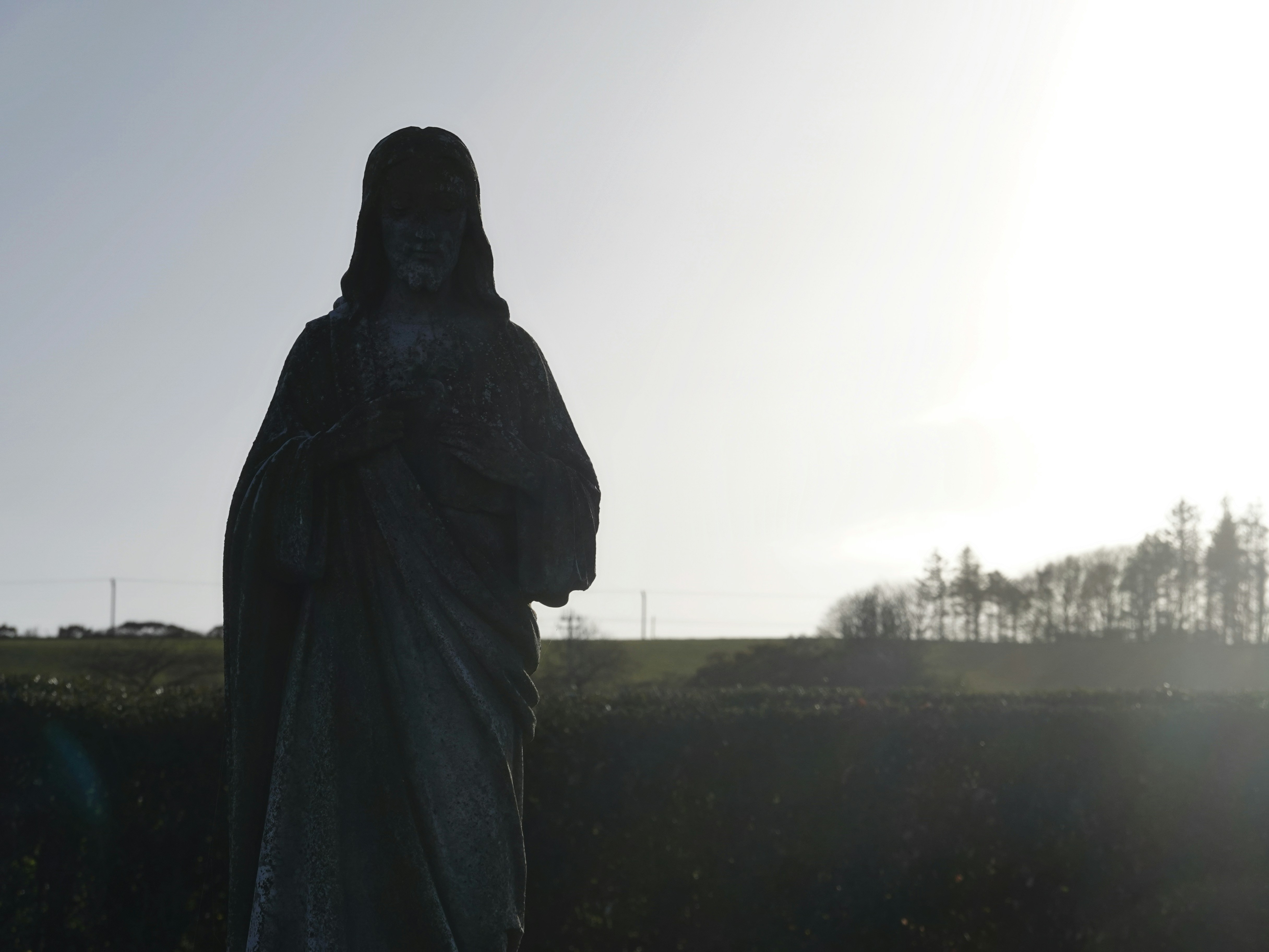 Shadowed Guardian: A Quiet Statue Under a Bleached Sky
