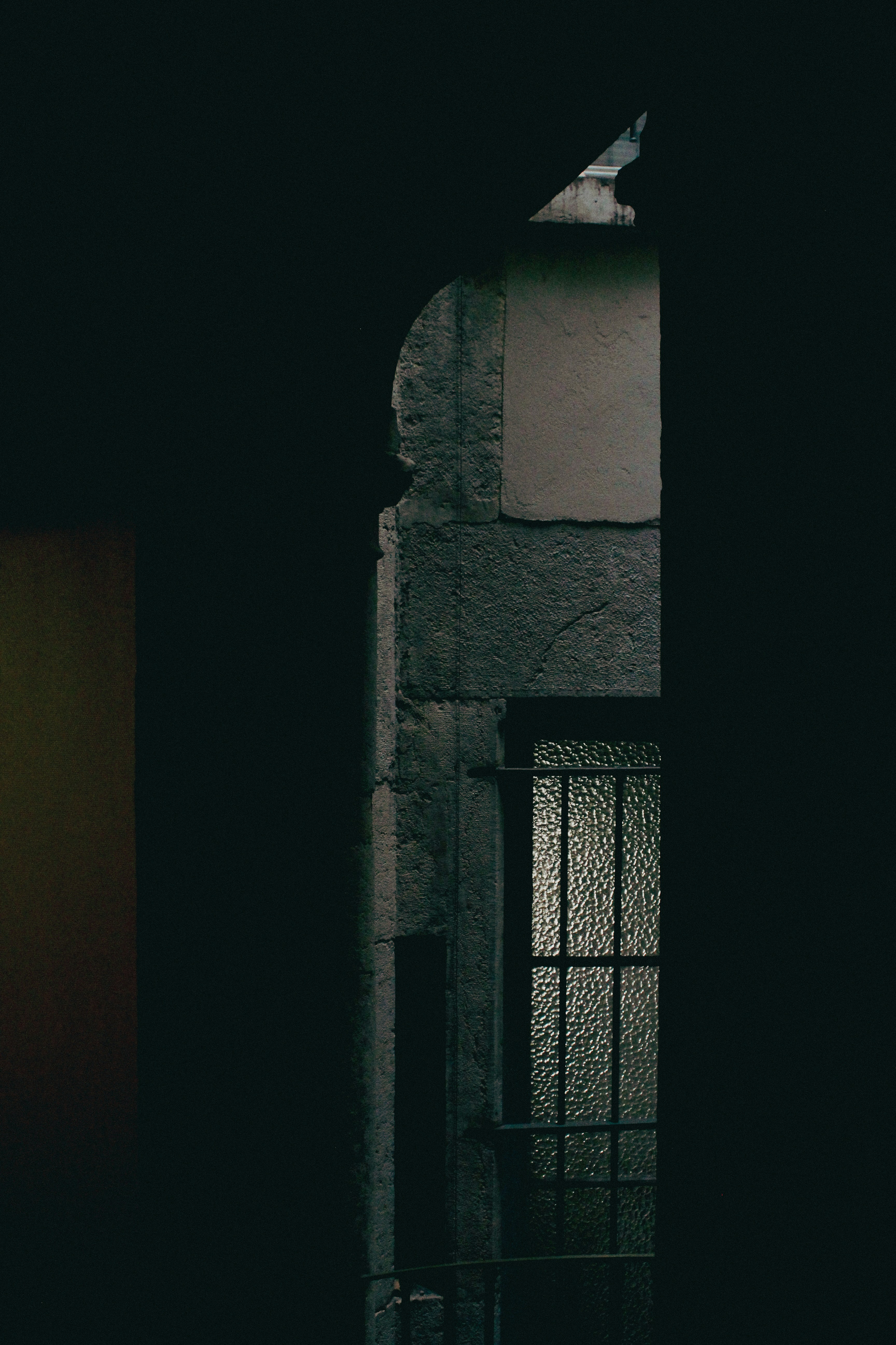 A Narrow View Through Archways: Dim Light Behind the Gridded Window