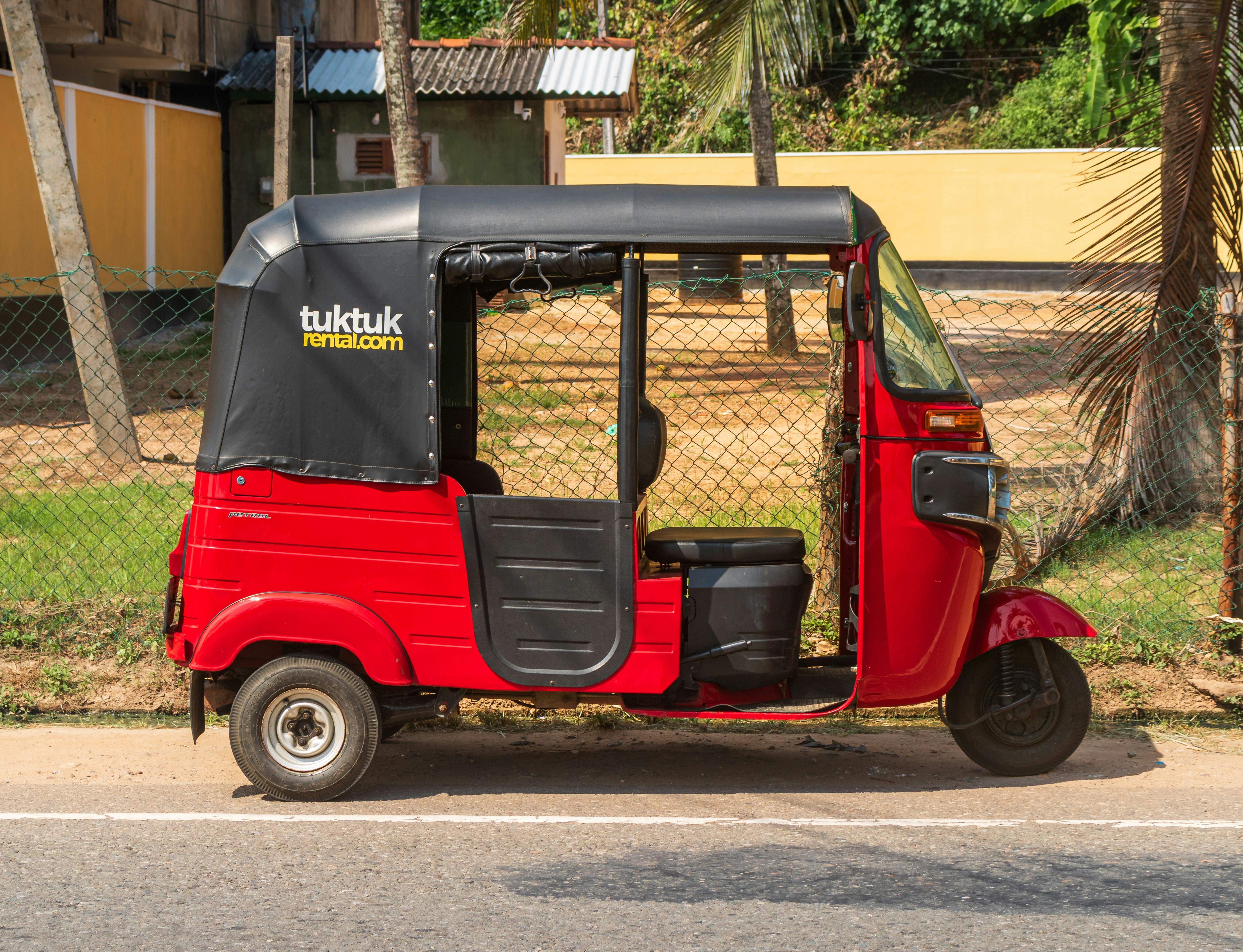 Red Tuk-Tuk at Sunlit Street: The Urban Courier of a Sunny Day