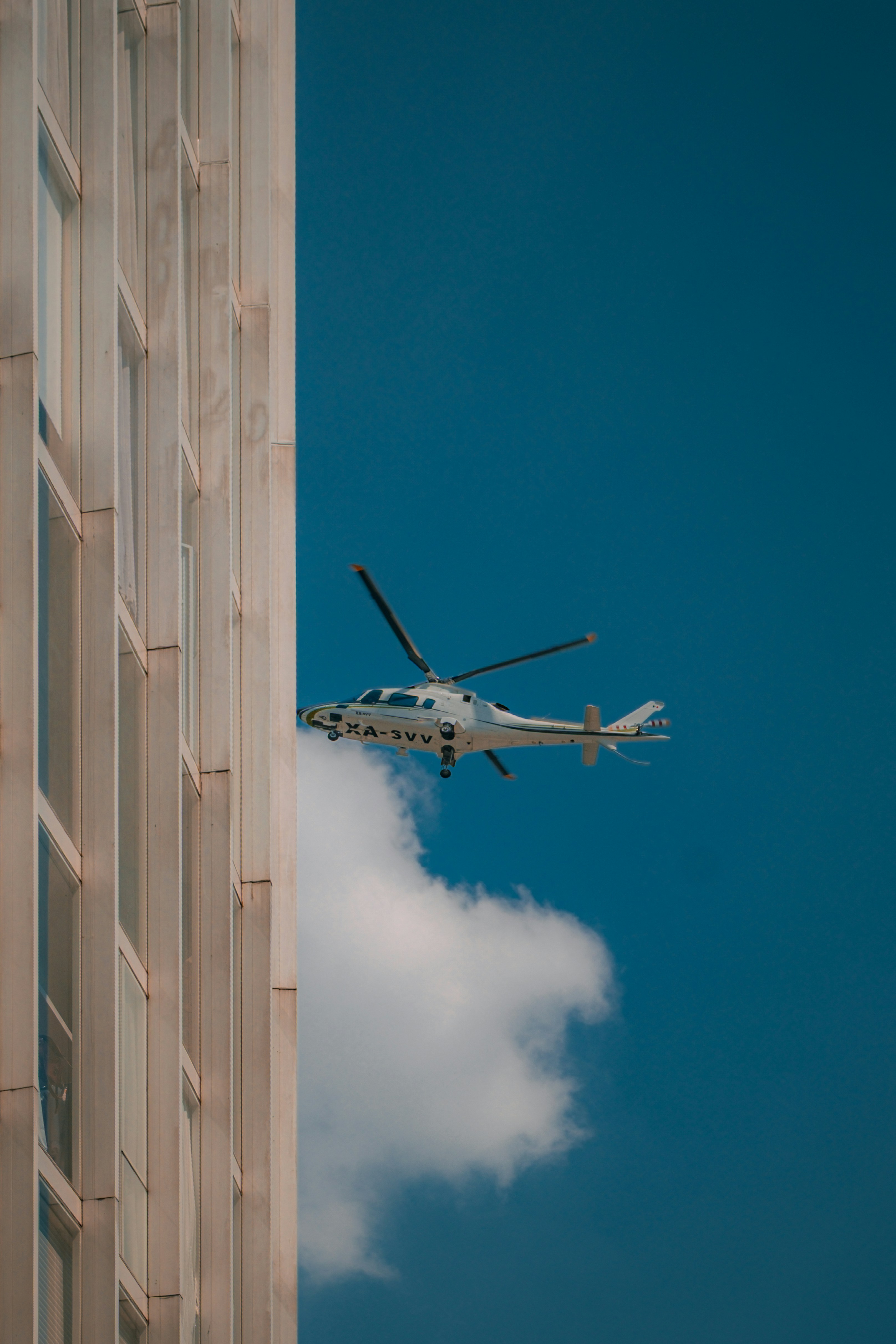 Helicopter Emerges Between Glass and Sky